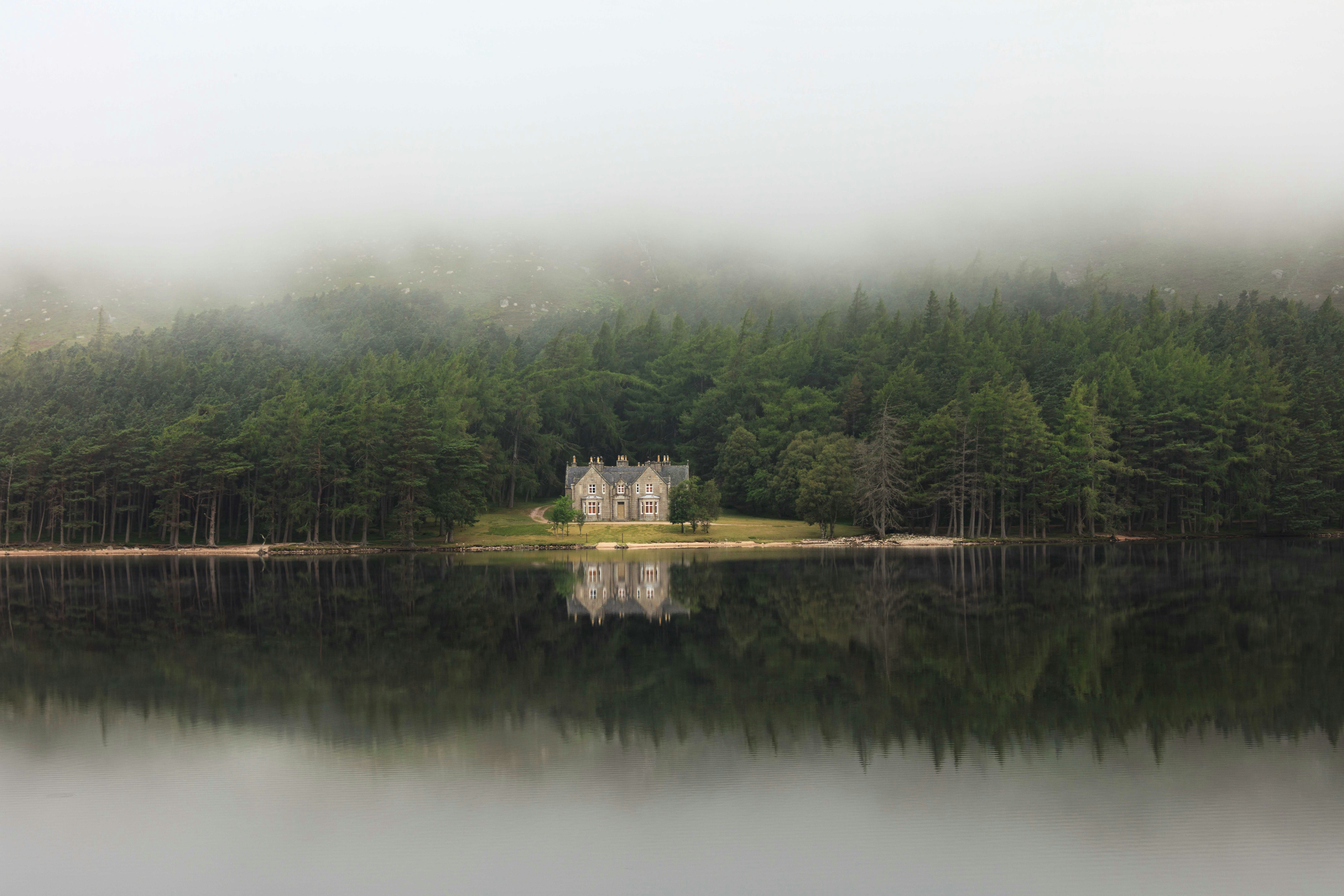 A building on a hill by a lake with trees photo – Free Loch muick Image ...