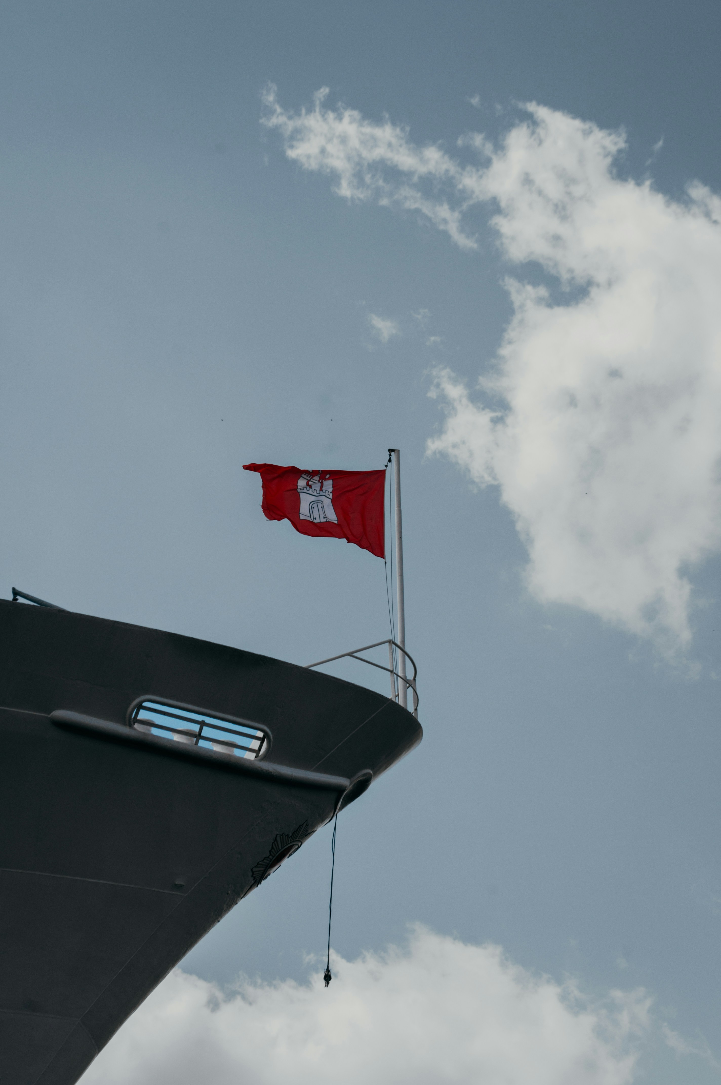 Scarlet Flag at the Bow: A Vivid Signal Against a Wide Blue Sky