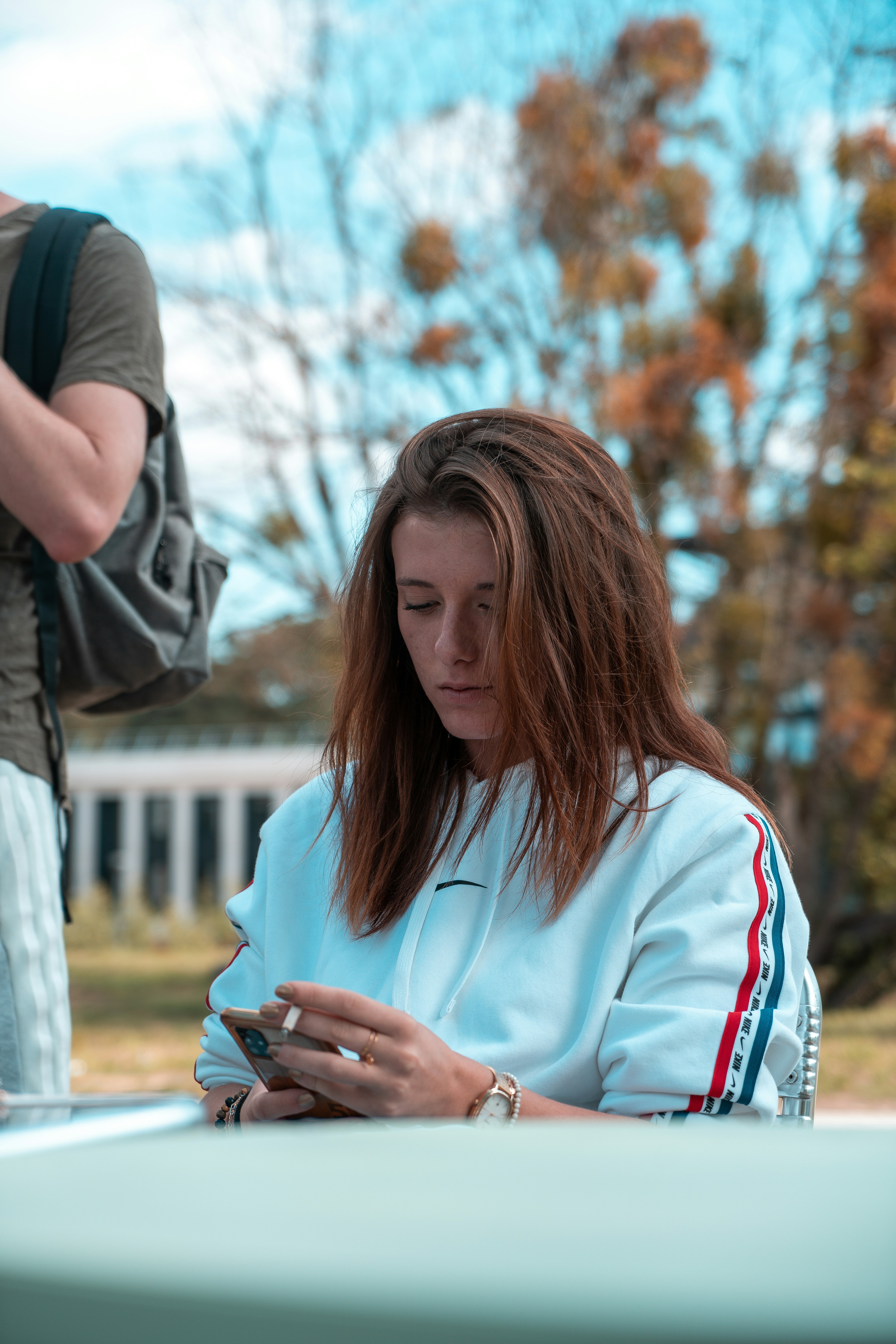 Focused Quiet: The Woman on Her Phone in a Sunlit Outdoor Scene