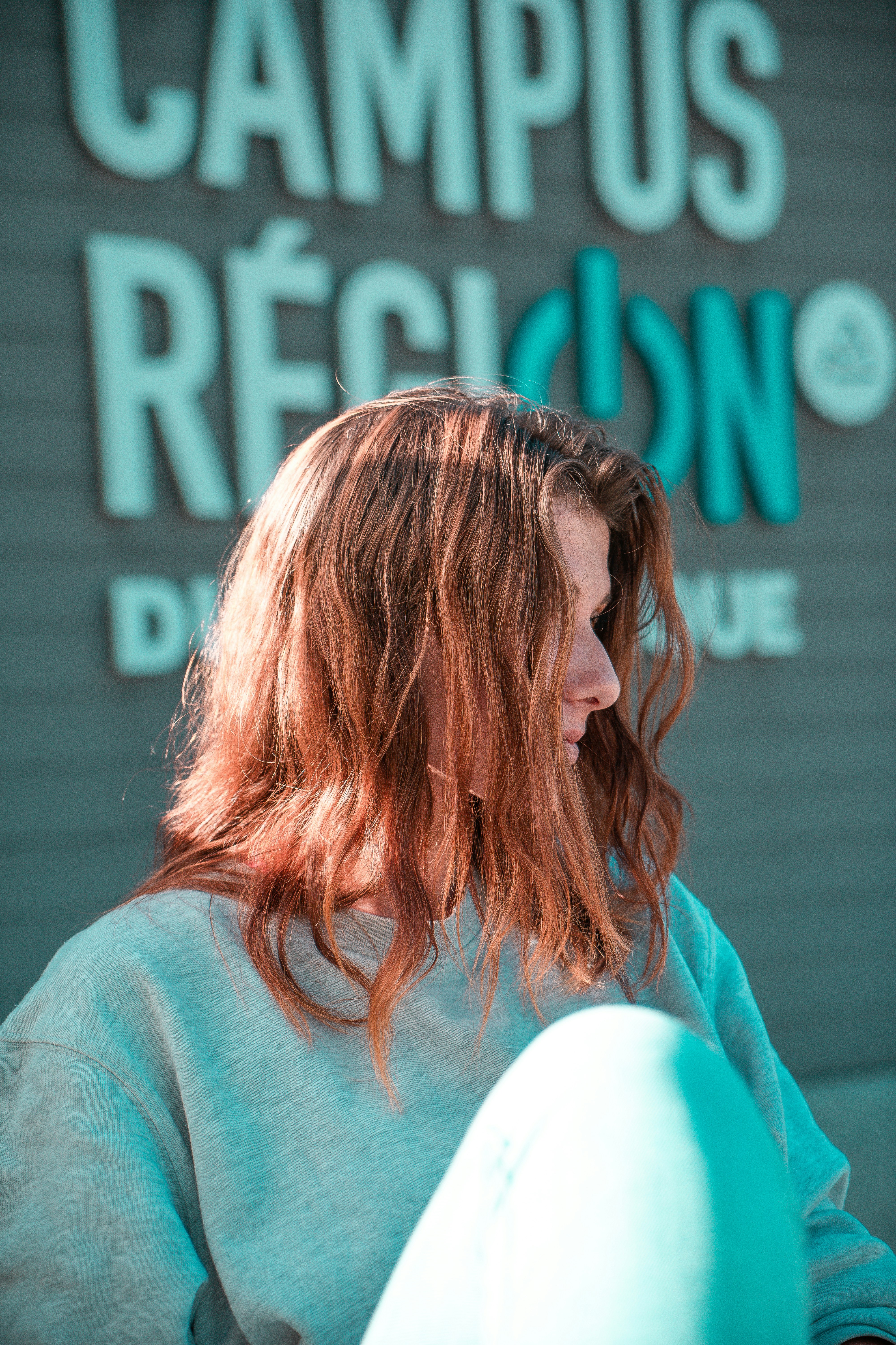 Muted teal hues and red-orange waves: a candid portrait against a bold campus sign