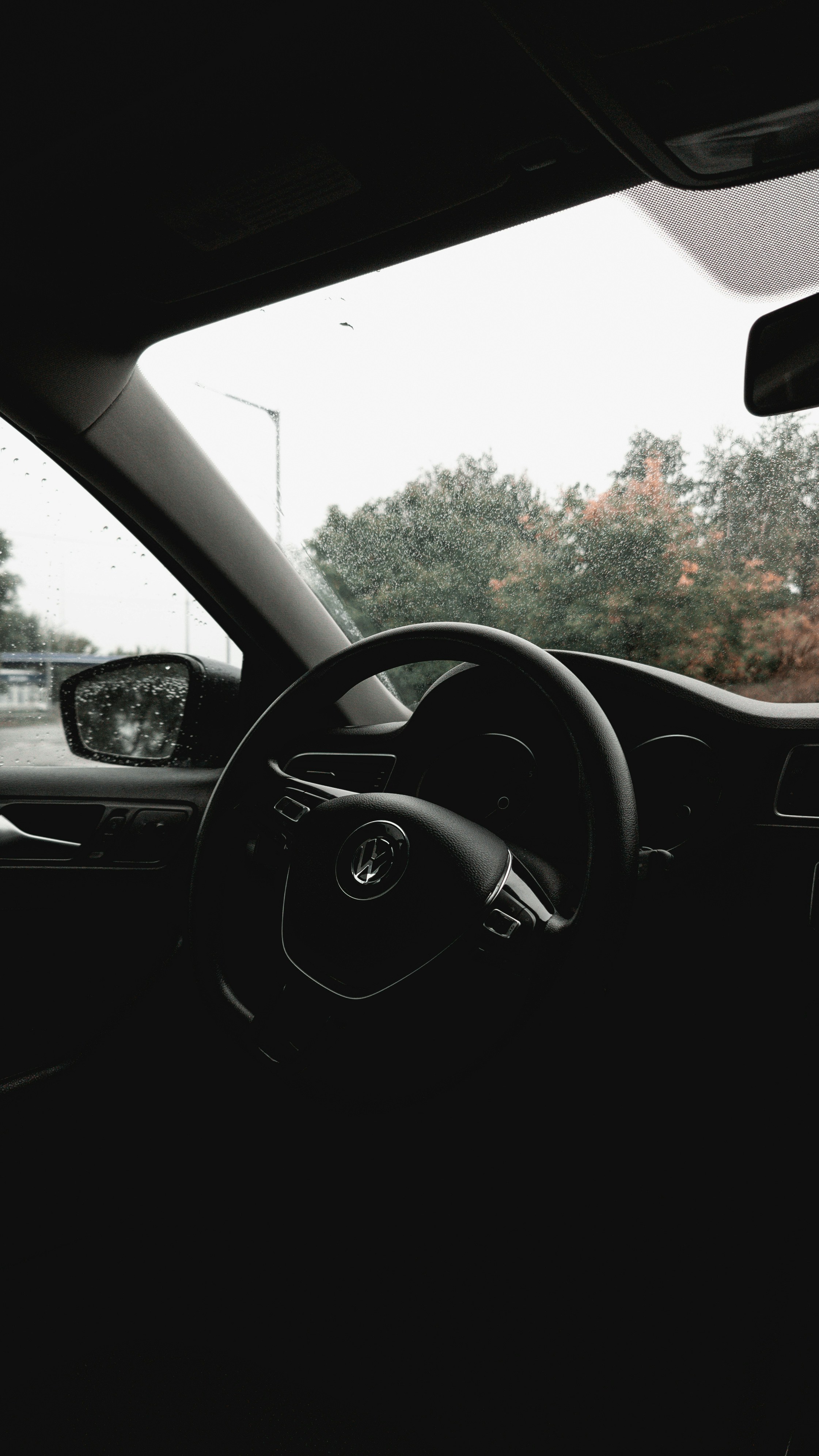 Rain-quiet VW Cockpit: A Dim Interior Framed by Rain-Streaked Windows