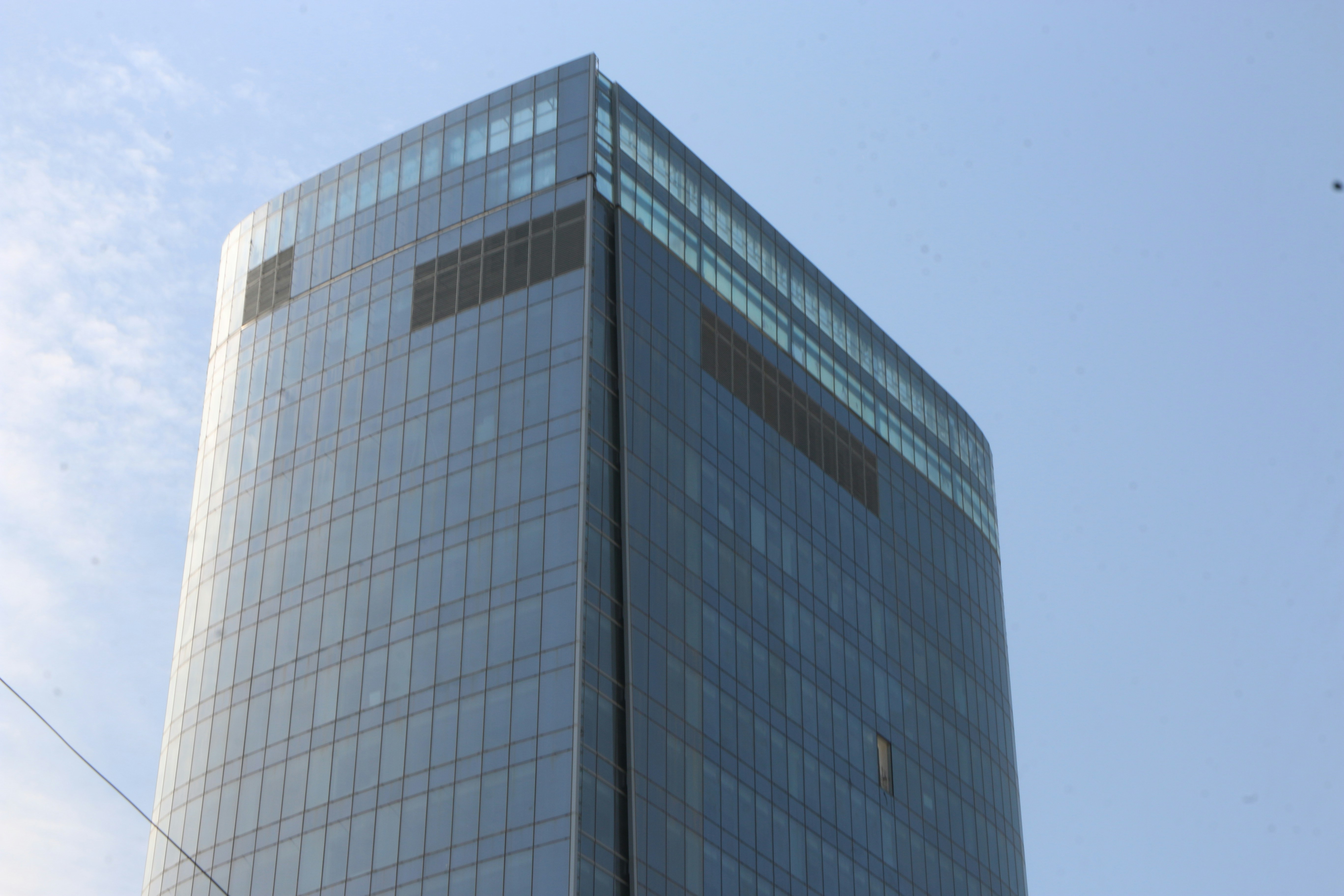 Tall modern skyscraper with a sleek glass exterior against a clear blue sky.