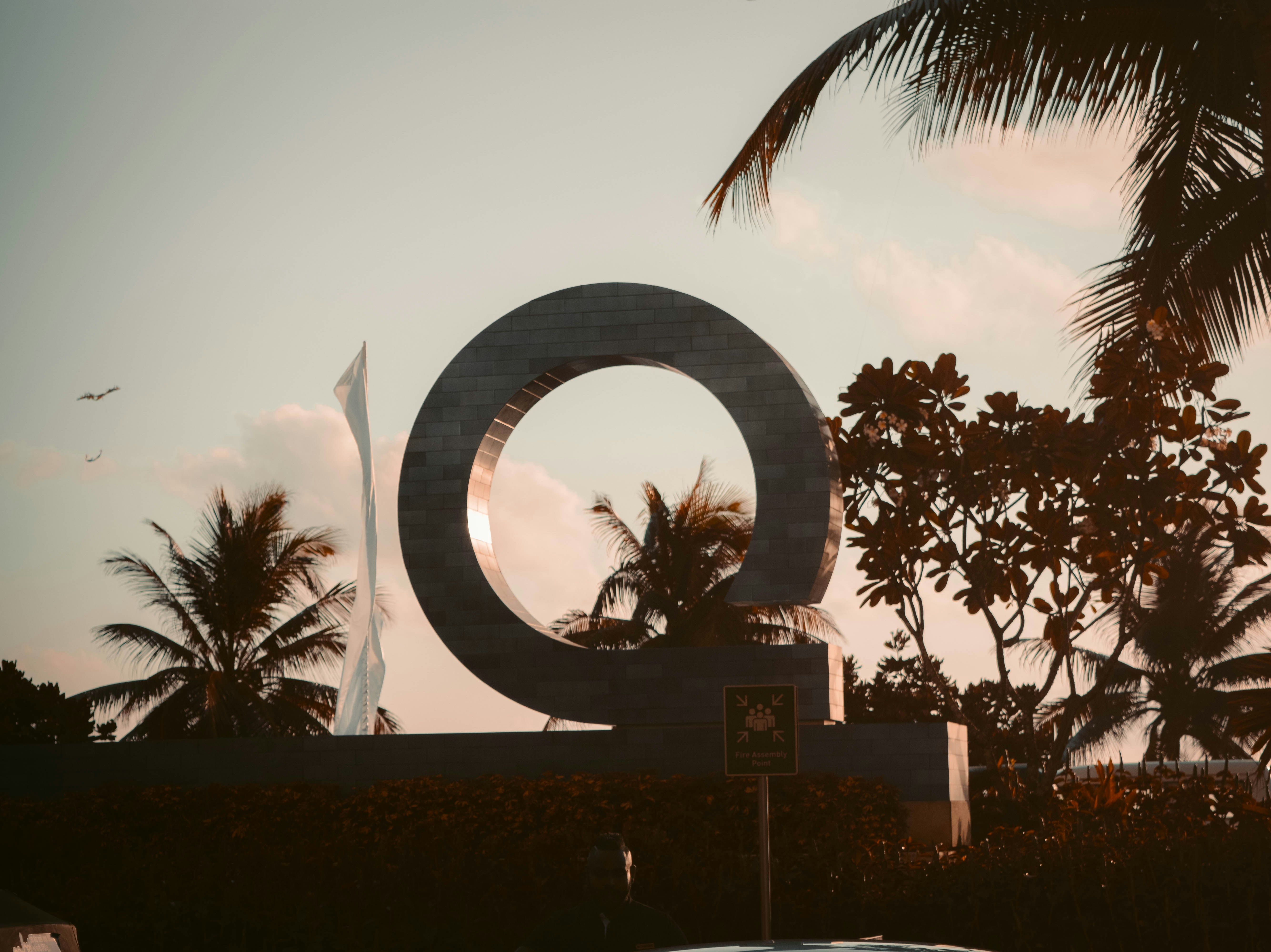 Dusk Ring: A Circular Monument Framed by Palms on a Seafront