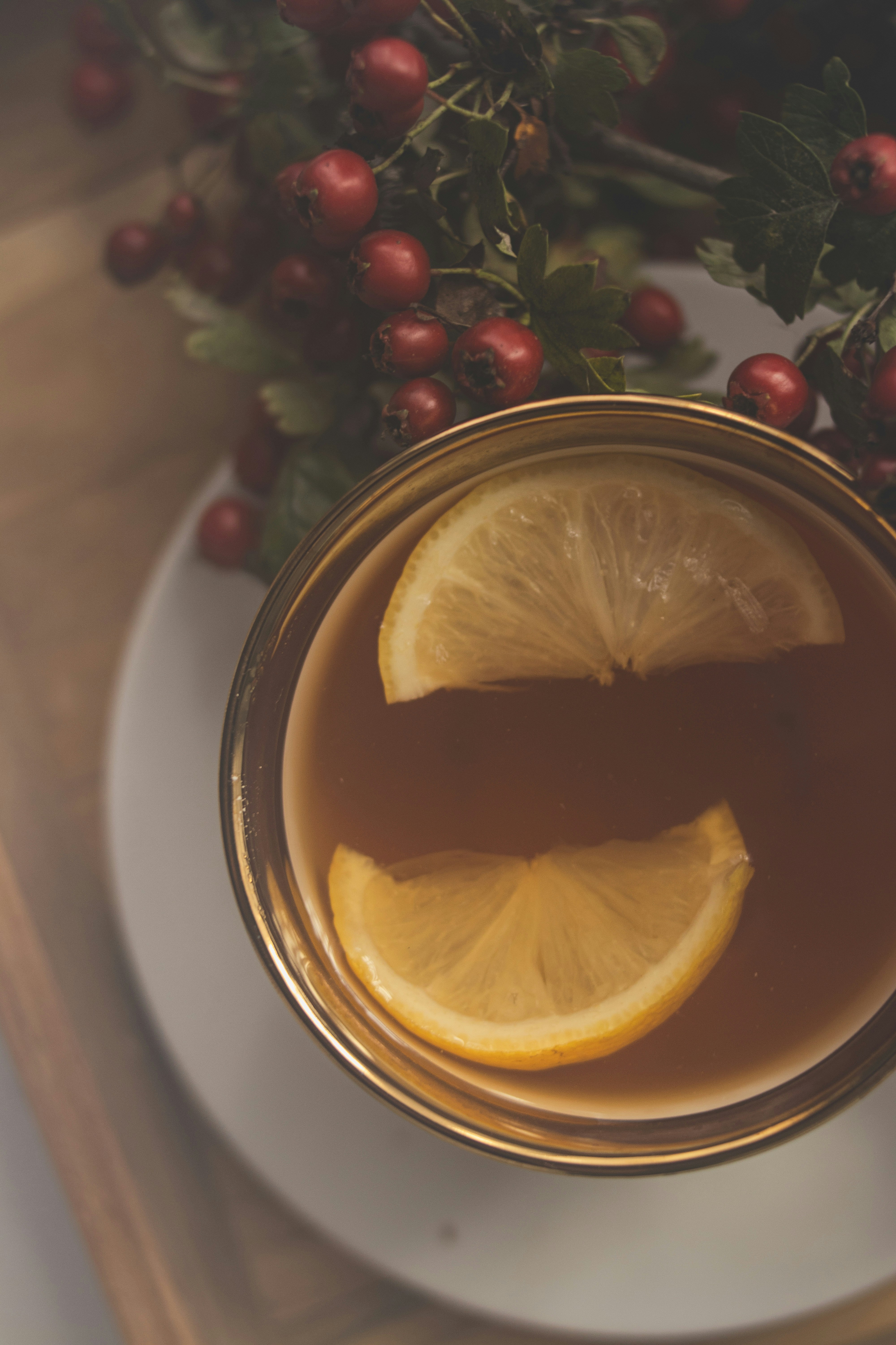 Citrus in Copper: A Cozy Glass Surrounded by Crimson Berries