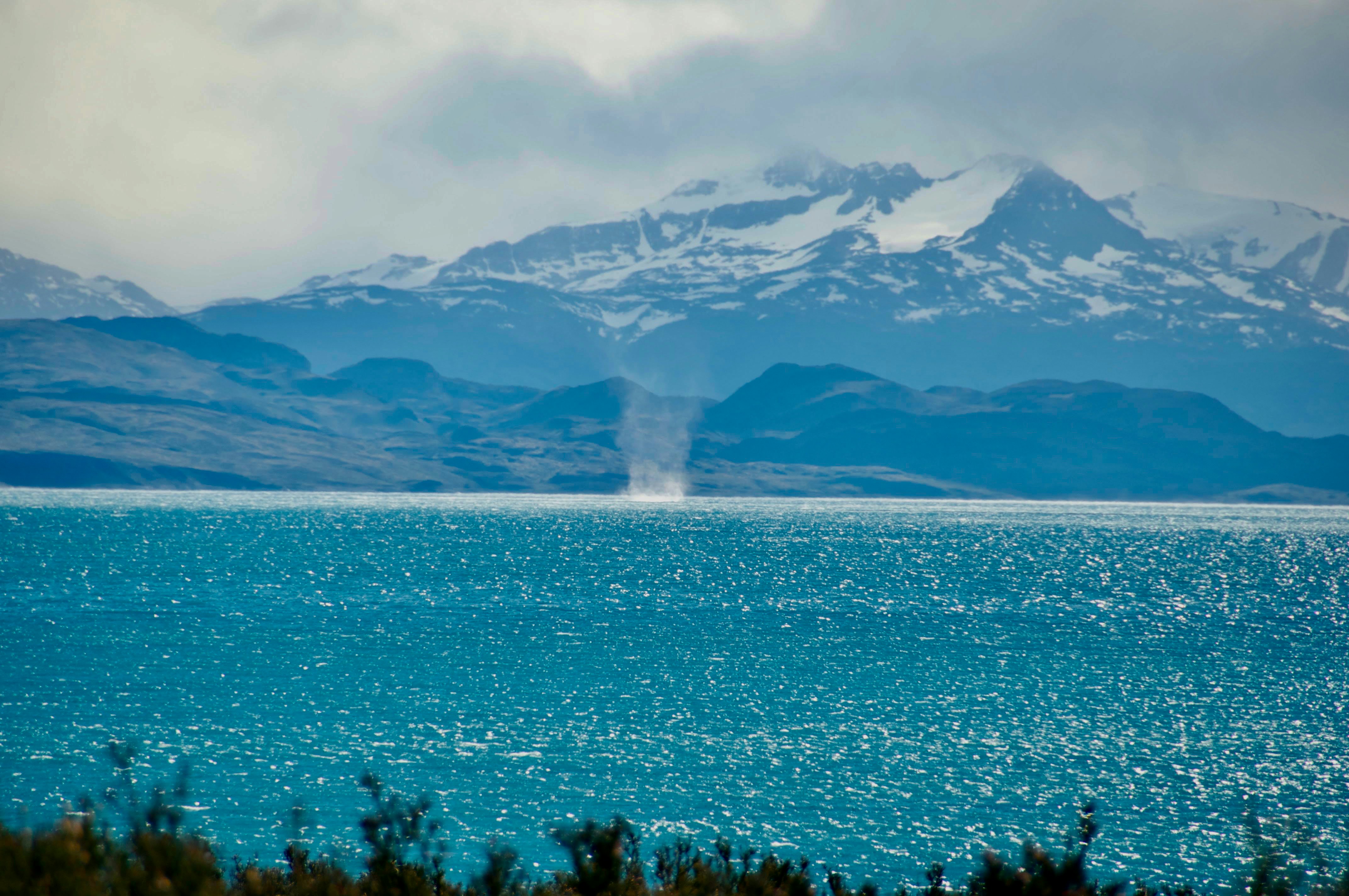 Turquoise Lake Under Alpine Peaks: A Quiet Geyser Breaks the Surface