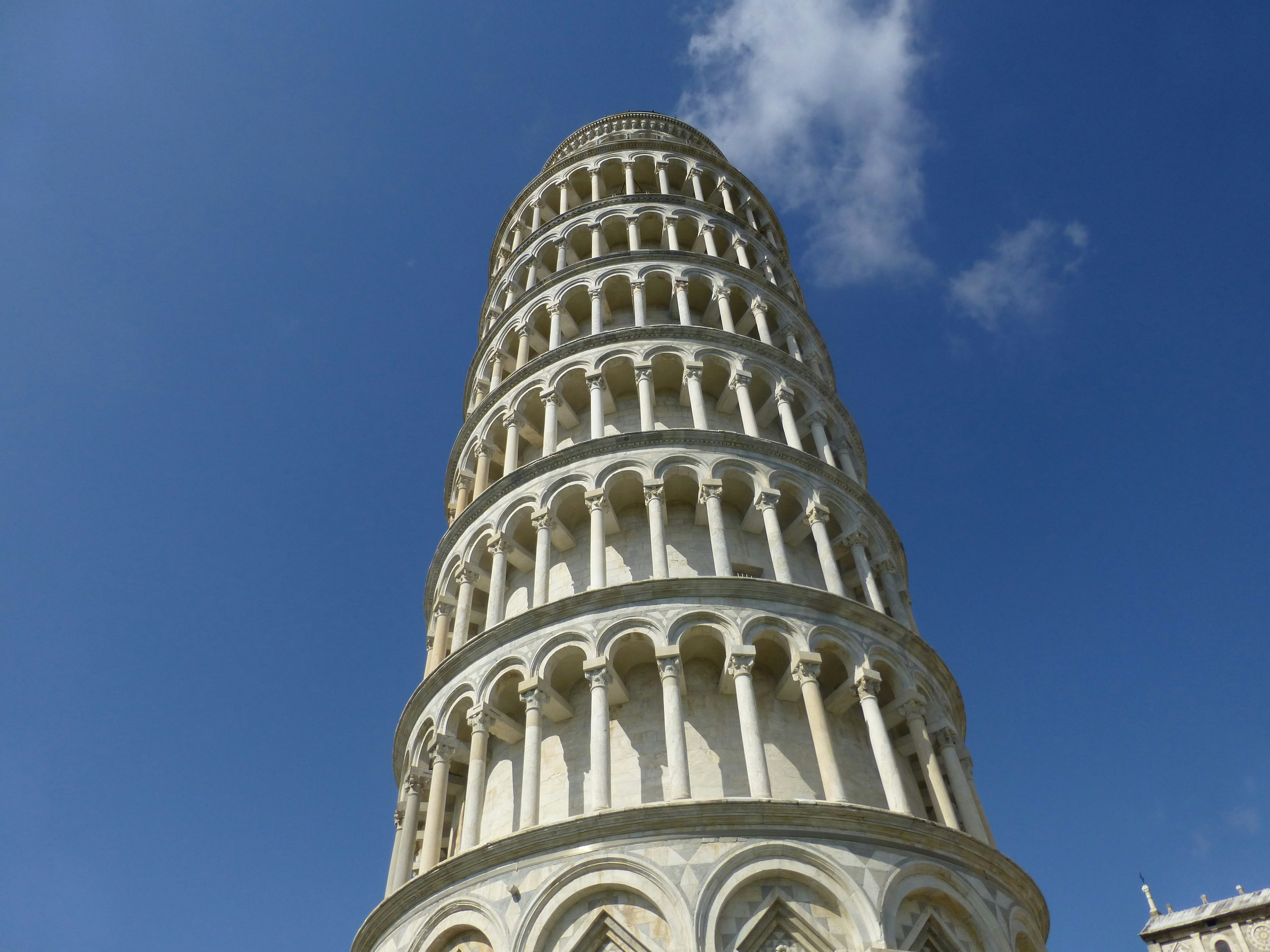 a tall white building with Leaning Tower of Pisa in the background