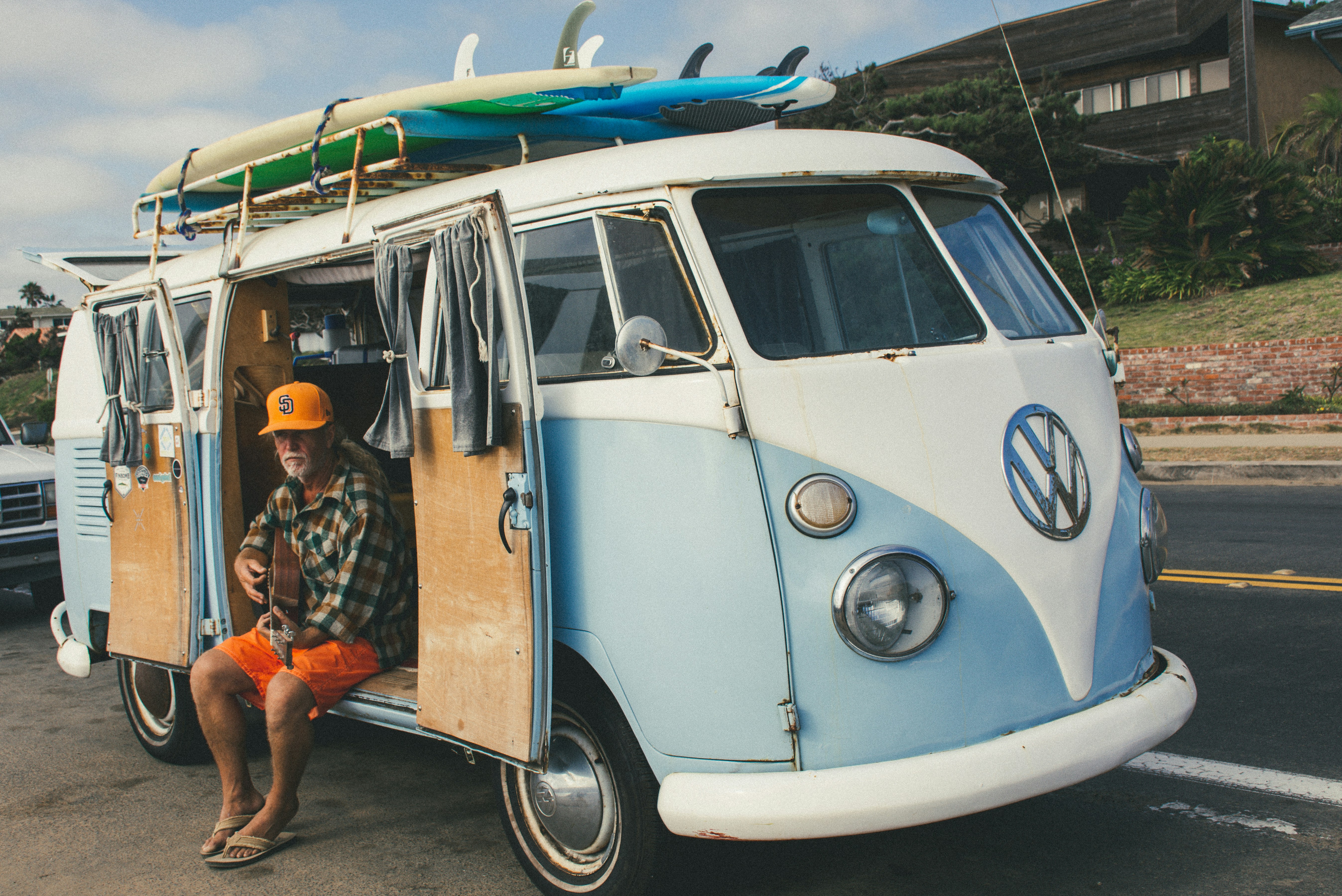 Man playing the acoustic guitar on his VW bus.