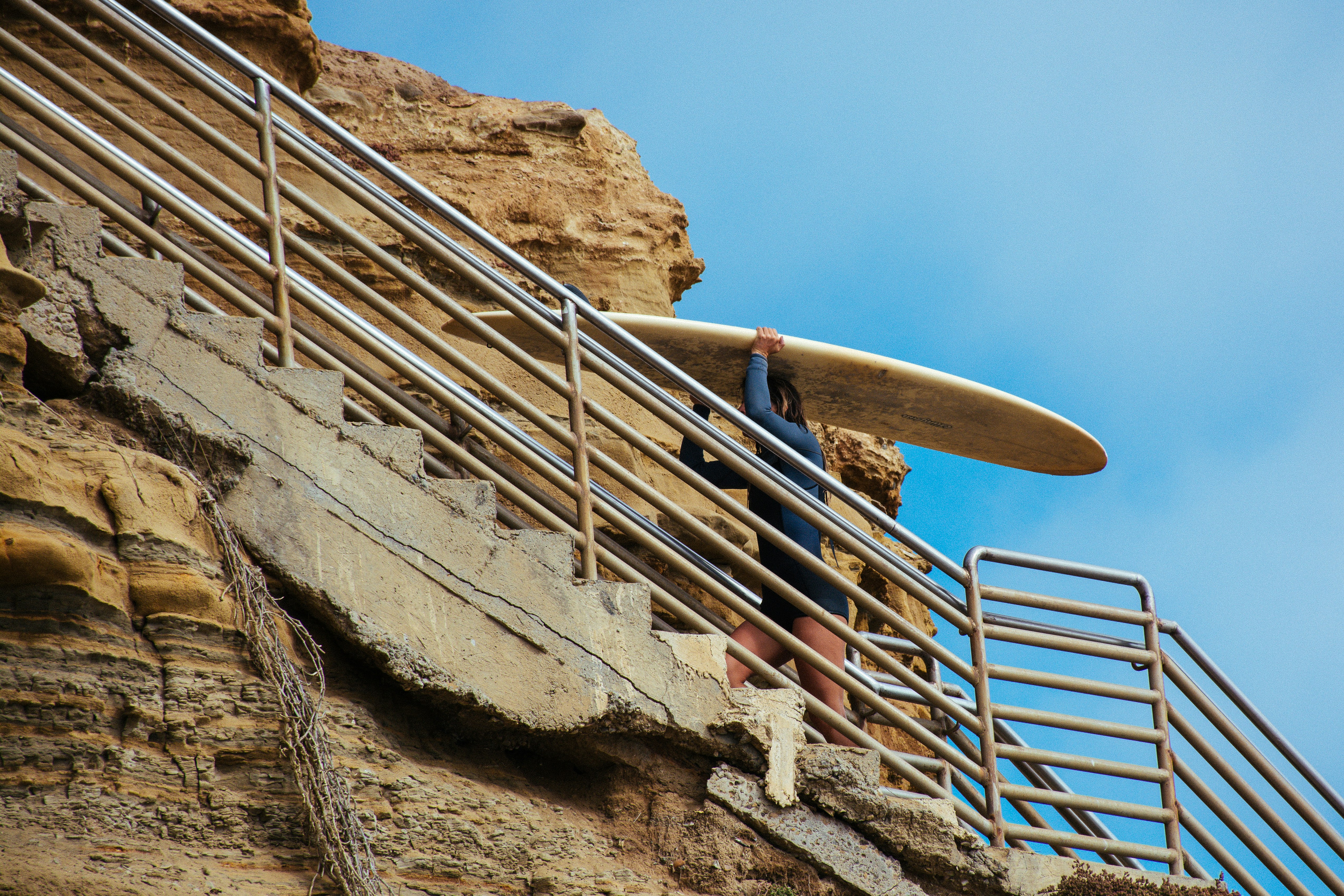Cliffside Balance: Surfboard Raised Over the Staircase