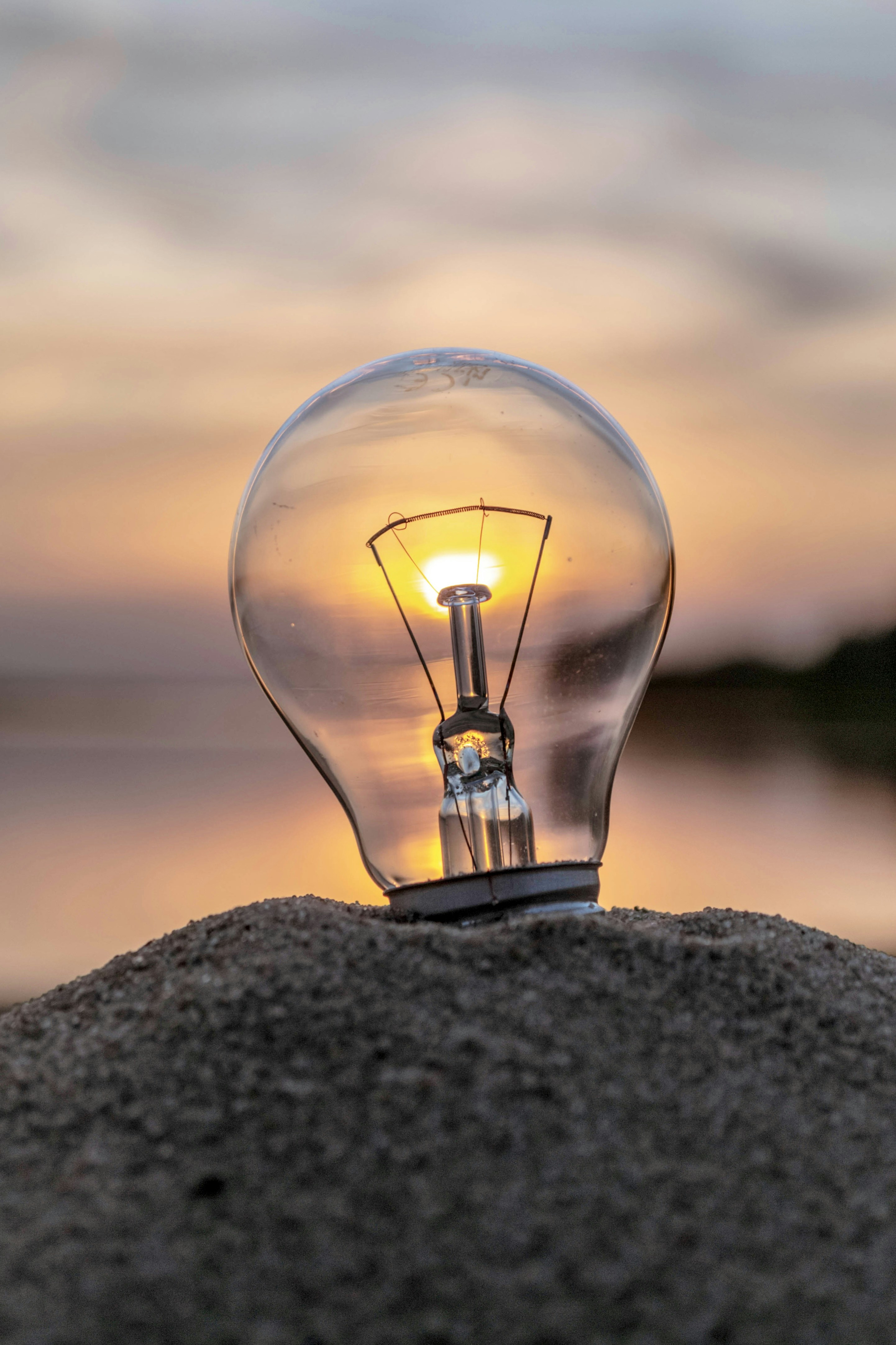 Glowing Bulb Nestled in Sand at Sunset