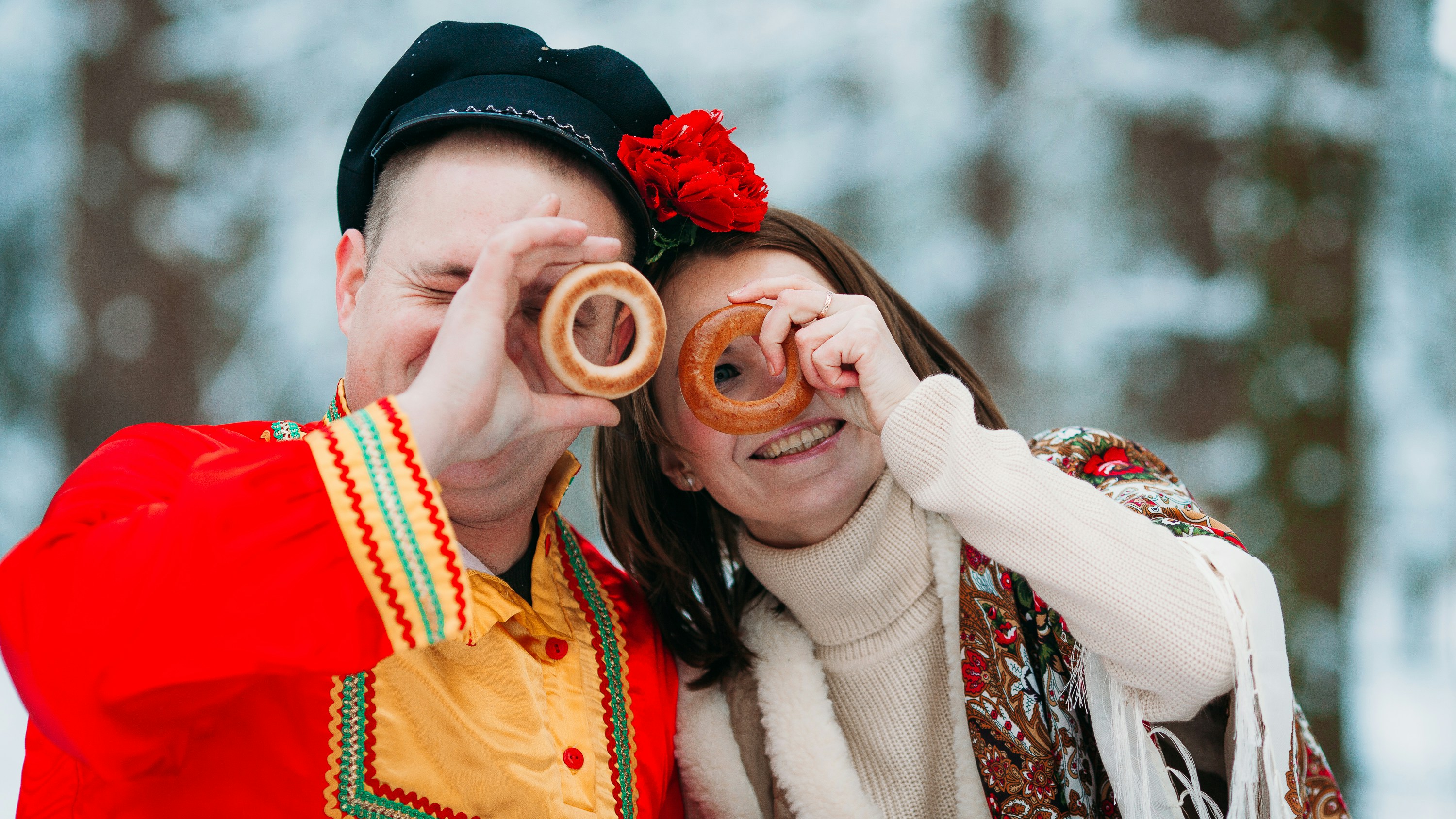 Pair in bright traditional attire peering through doughnut kismet rings