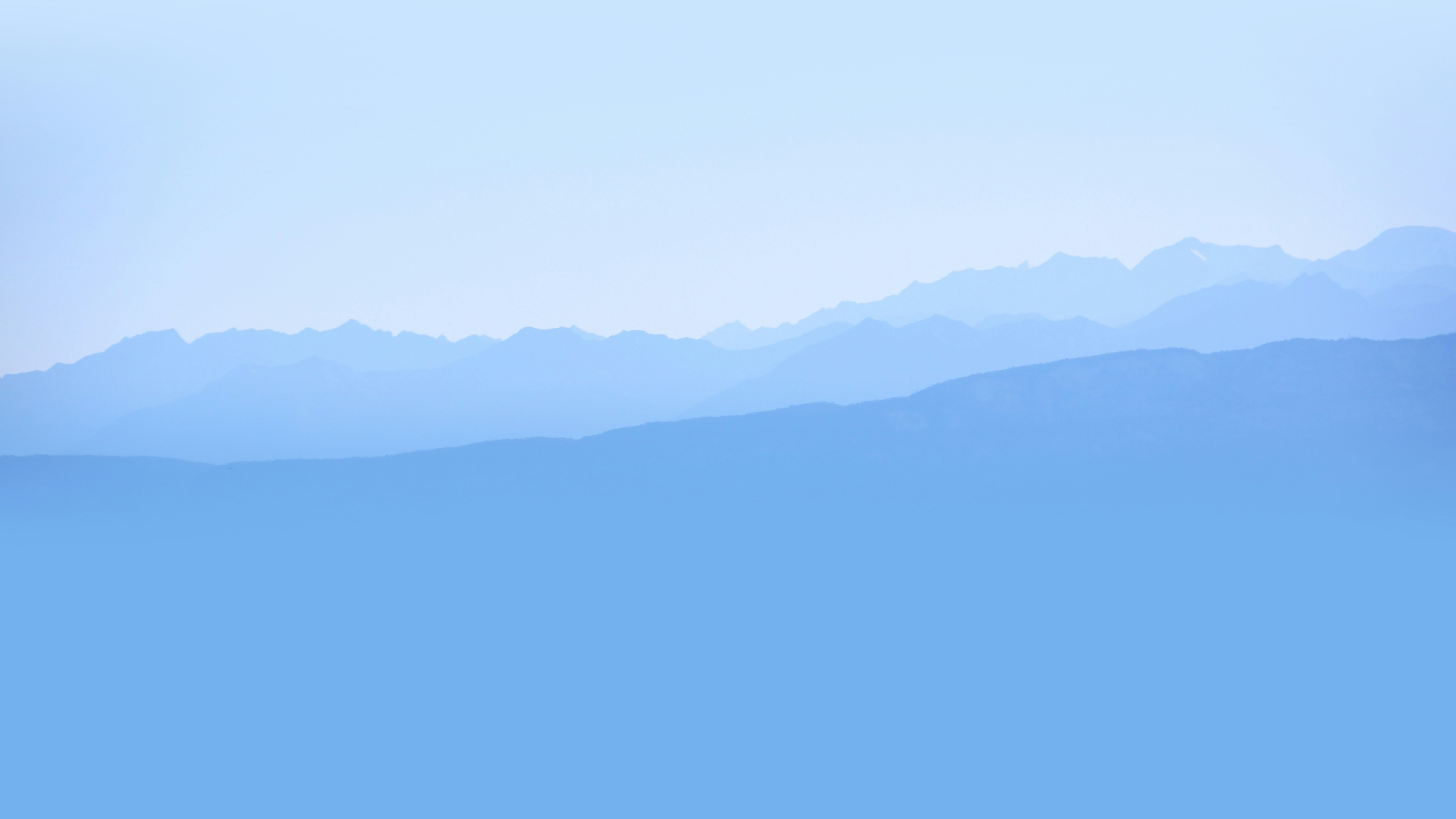 Soft layers of misty blue mountains under a pale sky.