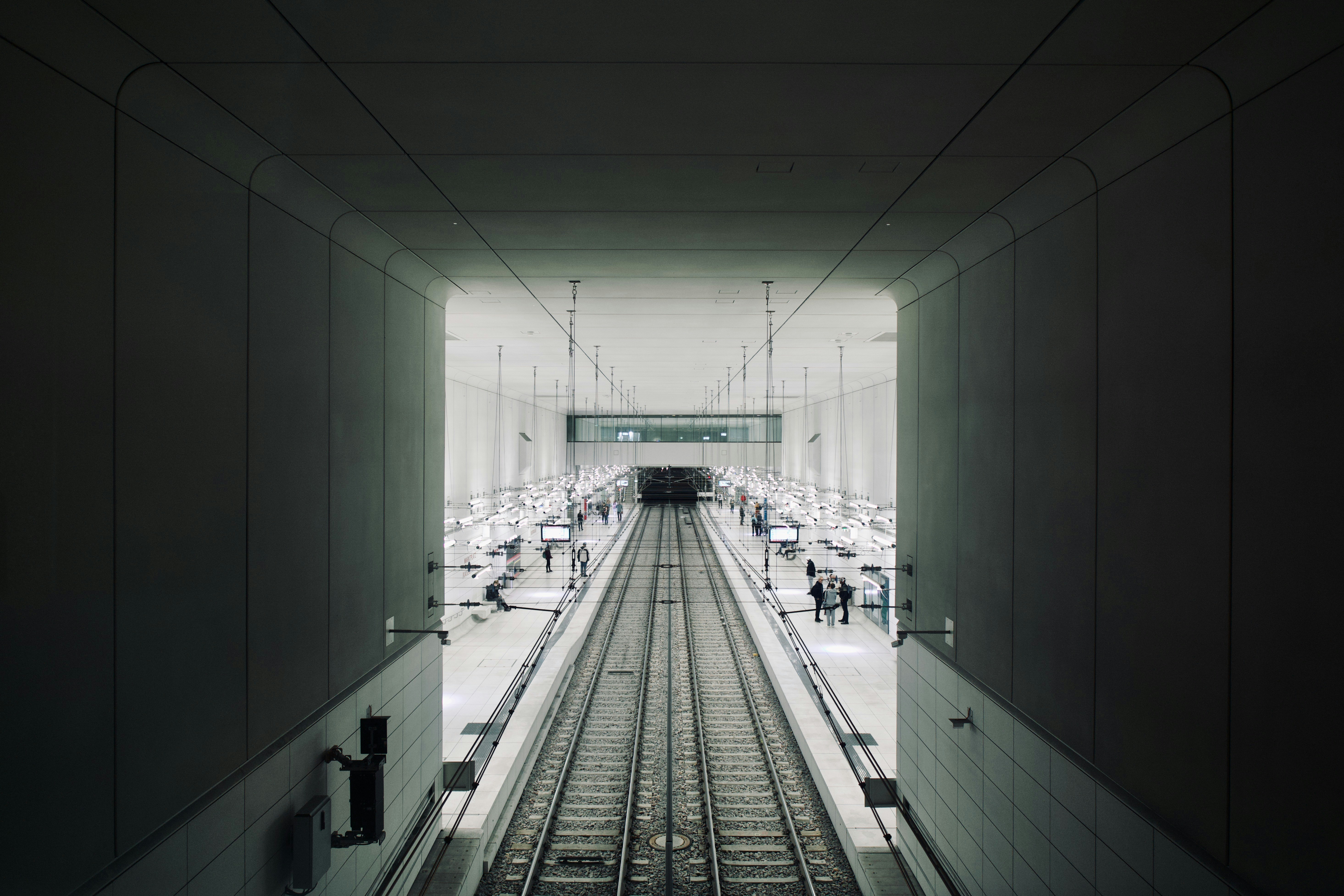 Modern train station with parallel tracks leading into a bright, symmetrical corridor.