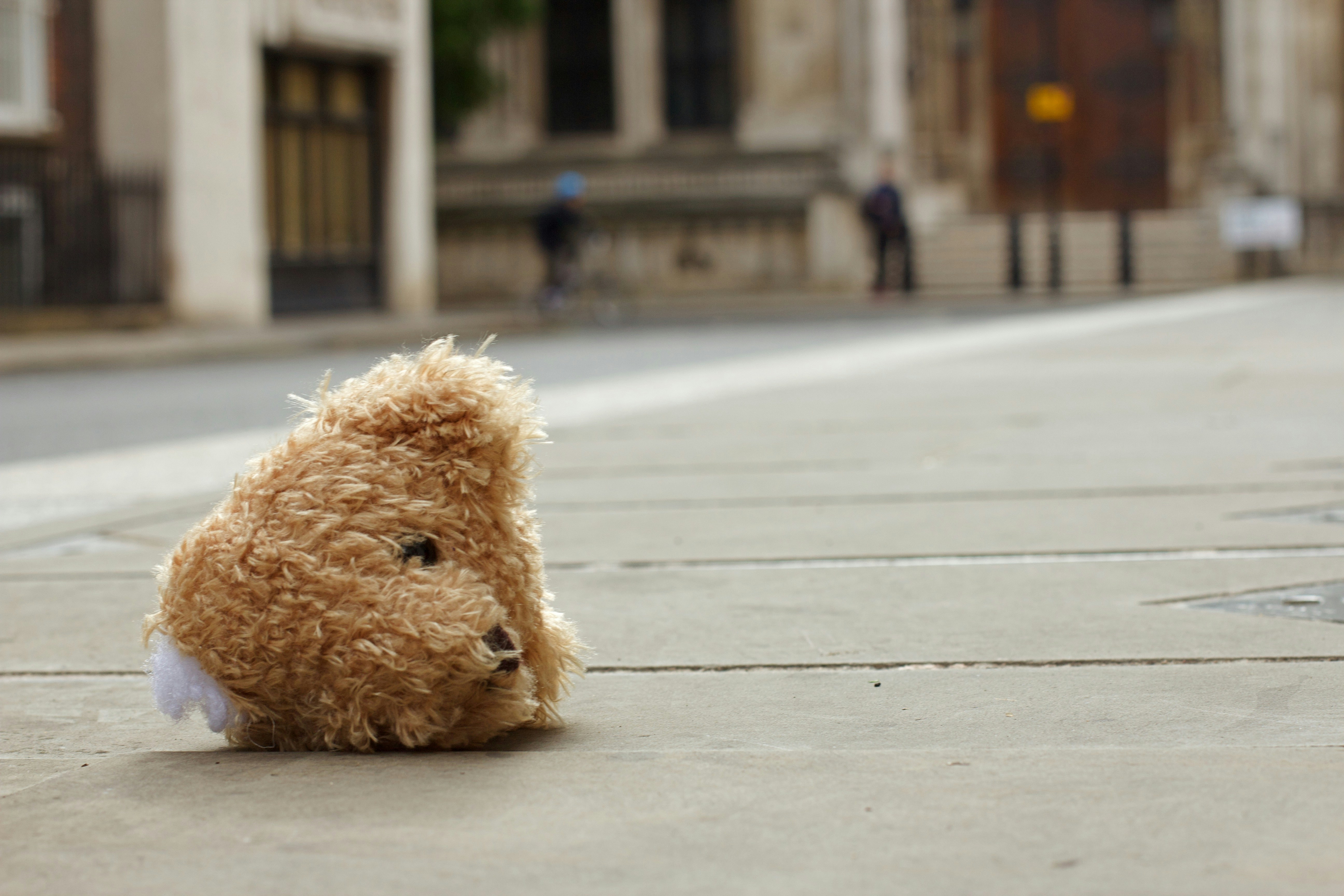 Lone teddy bear on a city sidewalk
