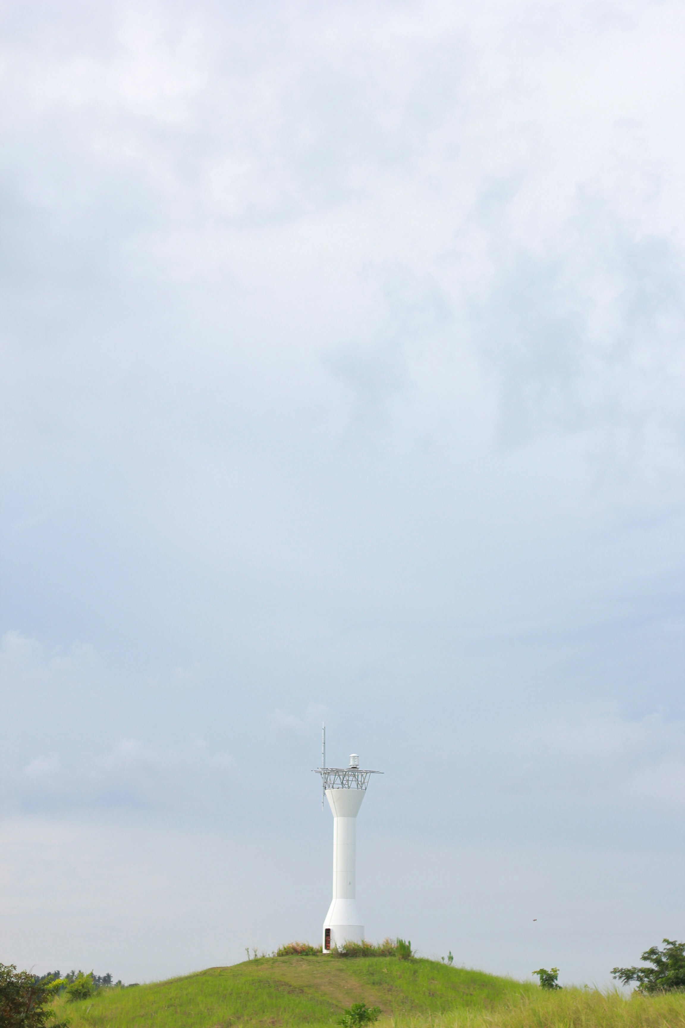 Vertical Sentinel on a Quiet Hilltop: White Tower Against an Expansive Sky