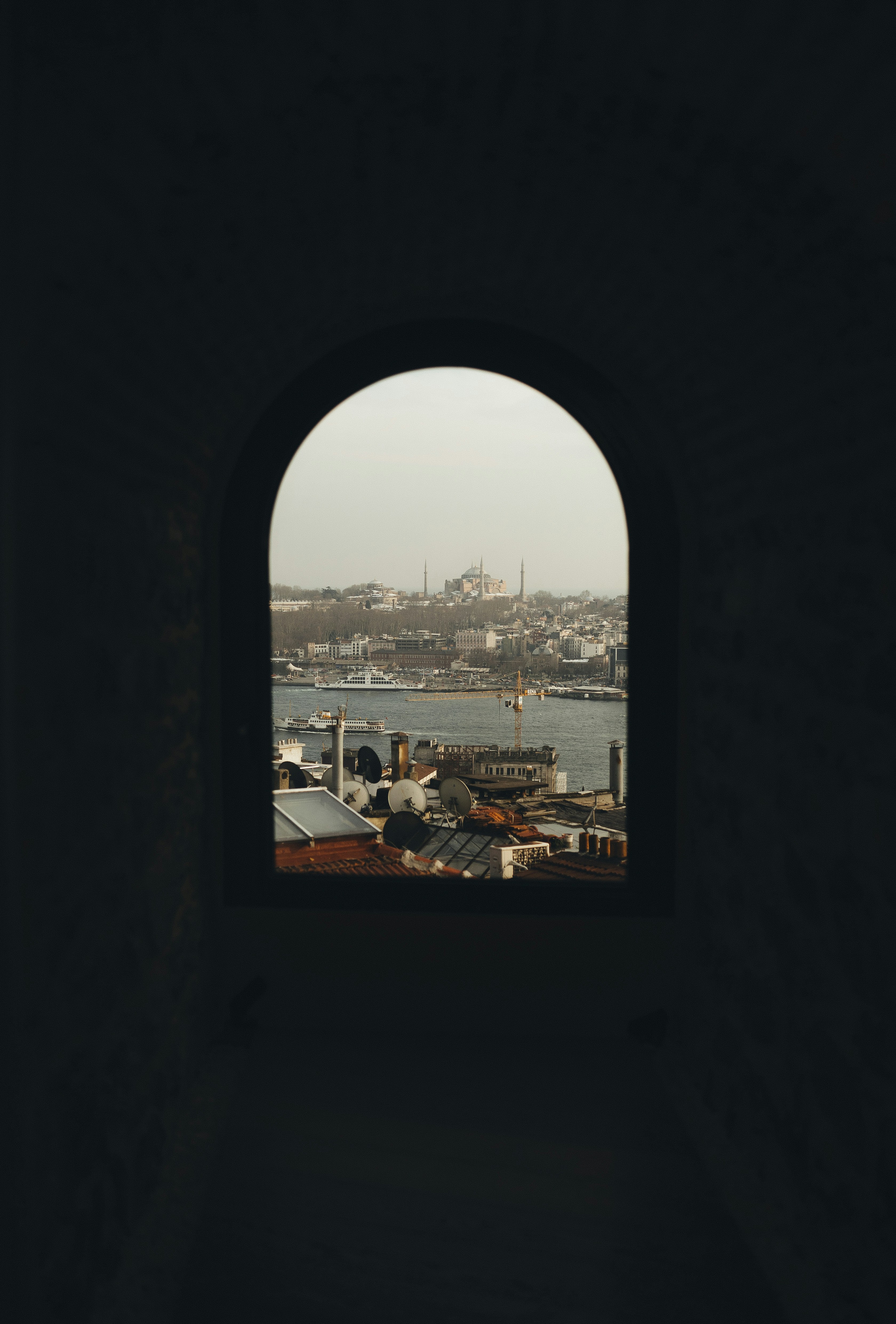 Archway Over a Waterfront Cityscape: Rooftops and Distant Minarets