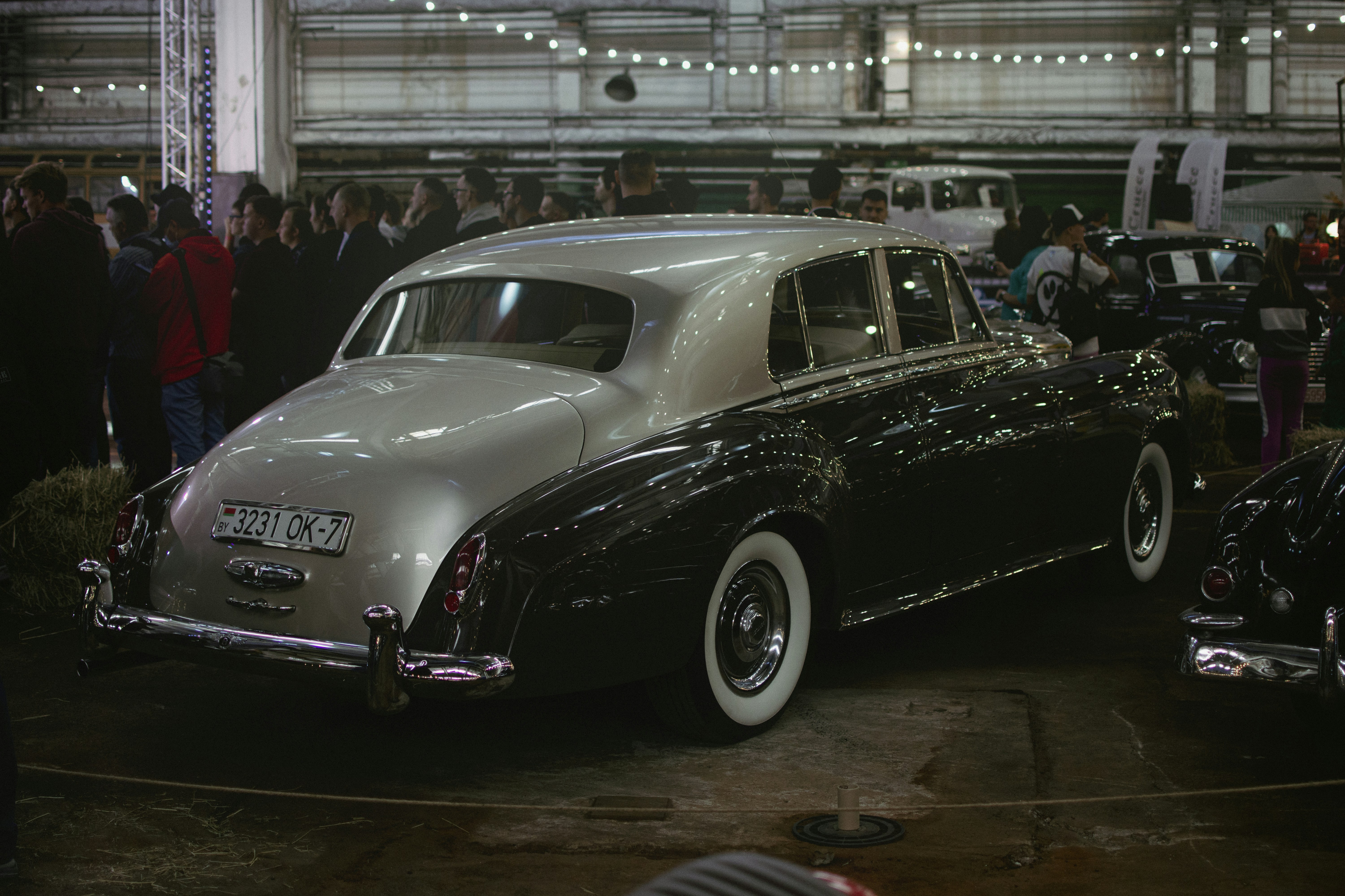 Two-Tone Vintage Sedan Surrounded by Enthusiasts