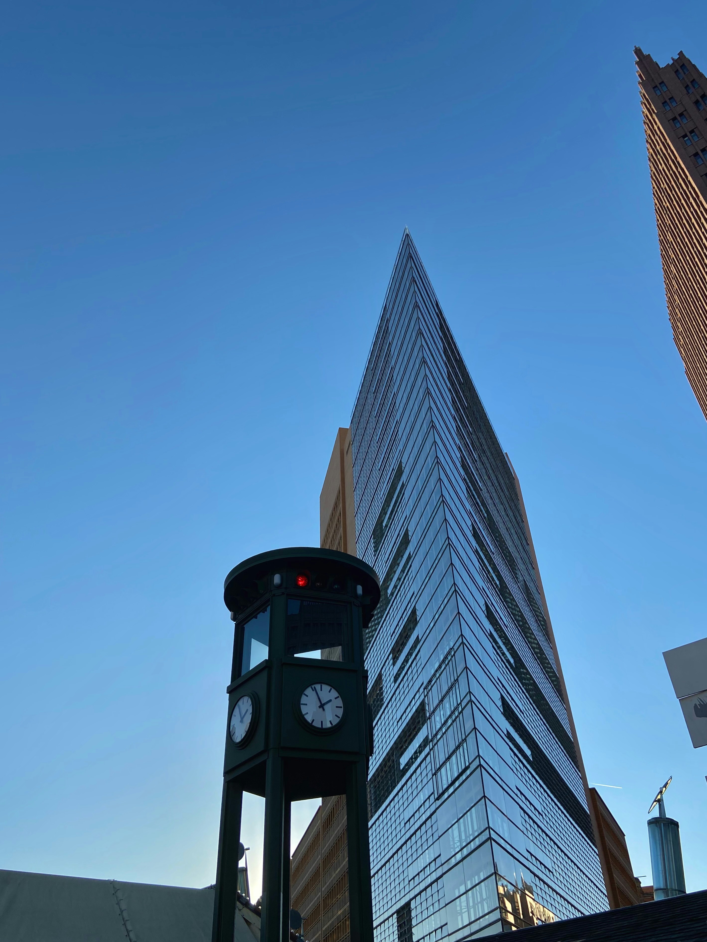 Apex of Blue Glass: The Triangular Tower Rising Over a Clock-Topped Foreground