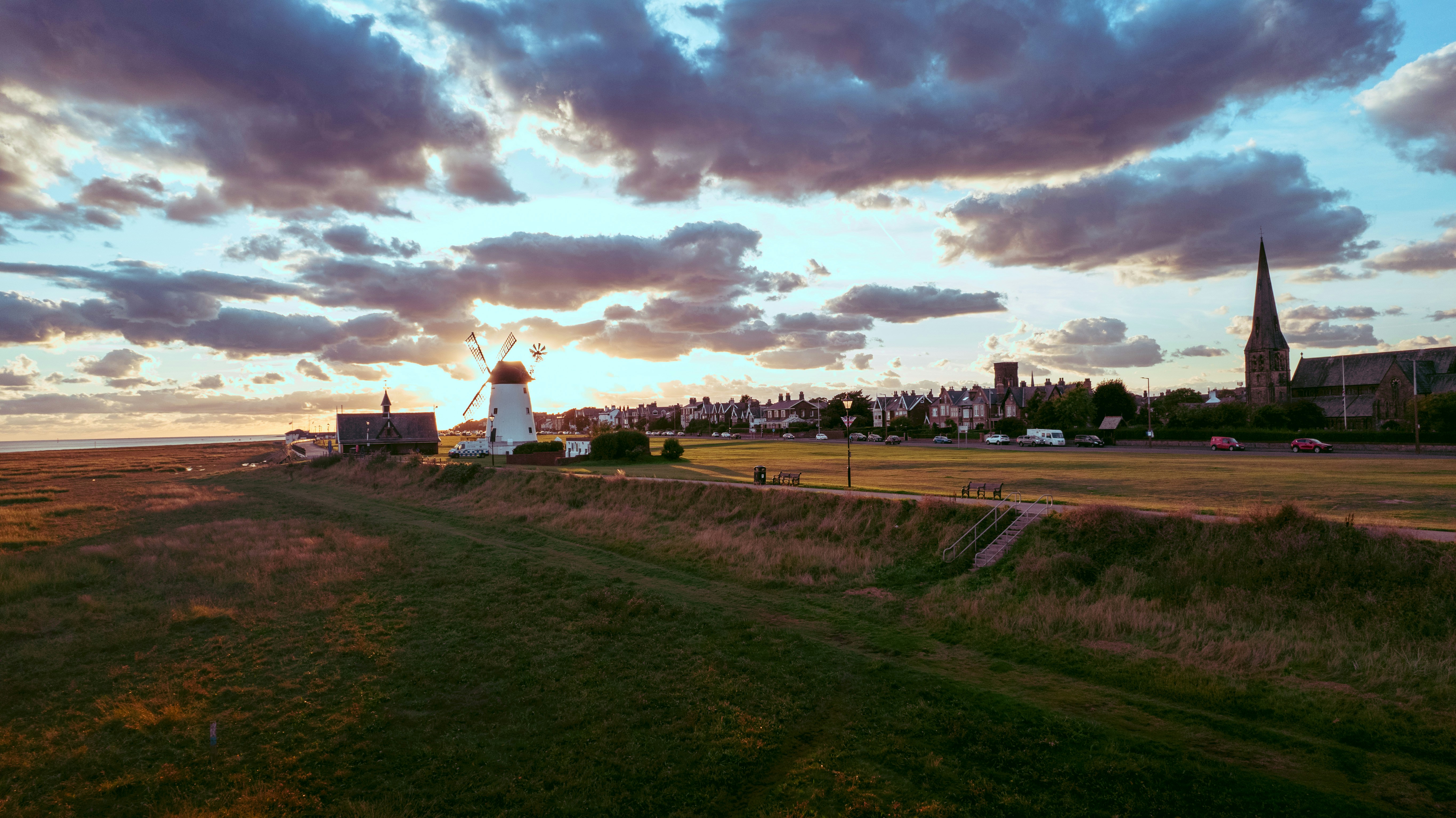 A large field with a white tower and a white building in the distance ...