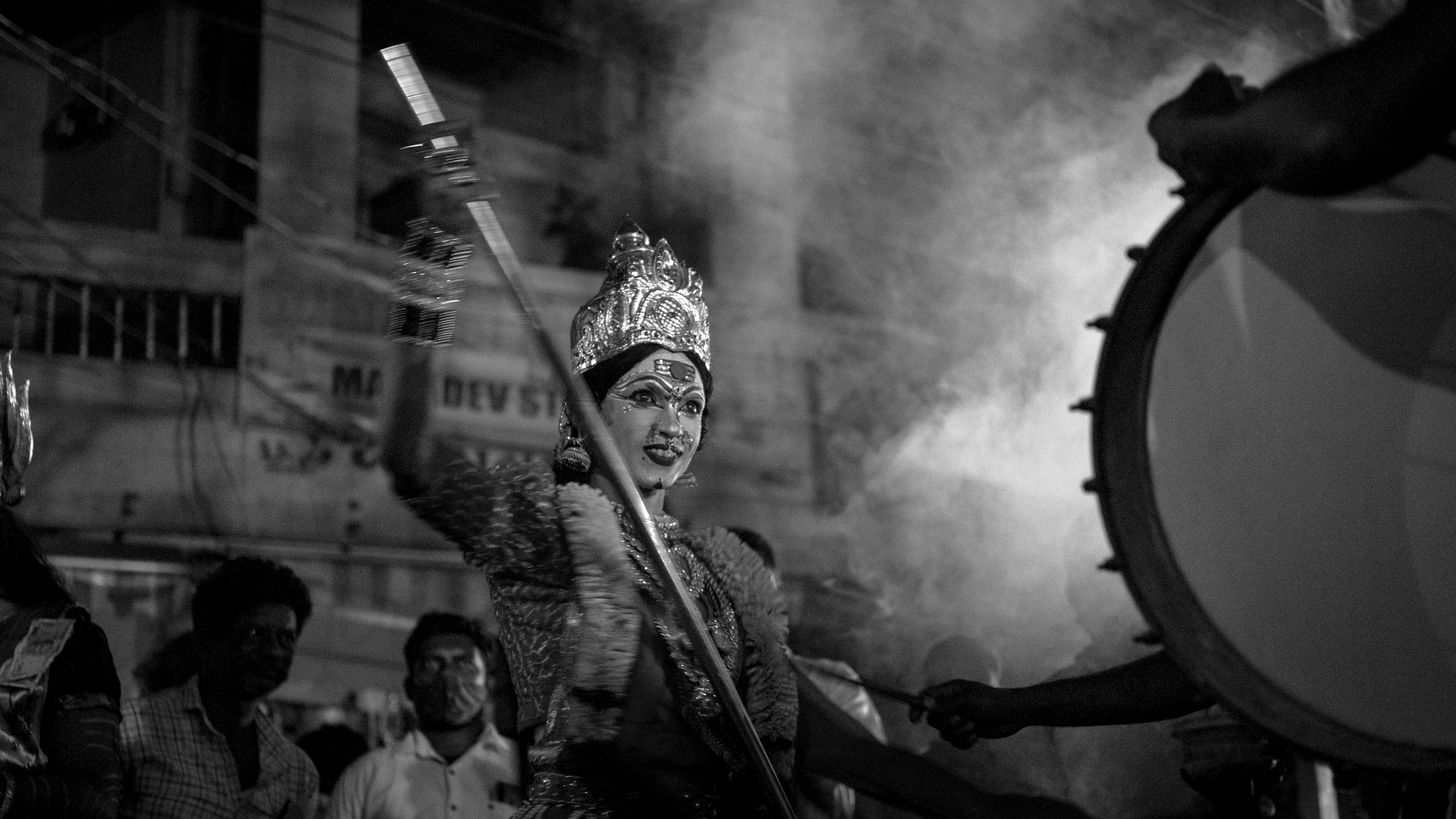 Crowned Warrior Raises a Spear Amid Drumbeat and Smoke