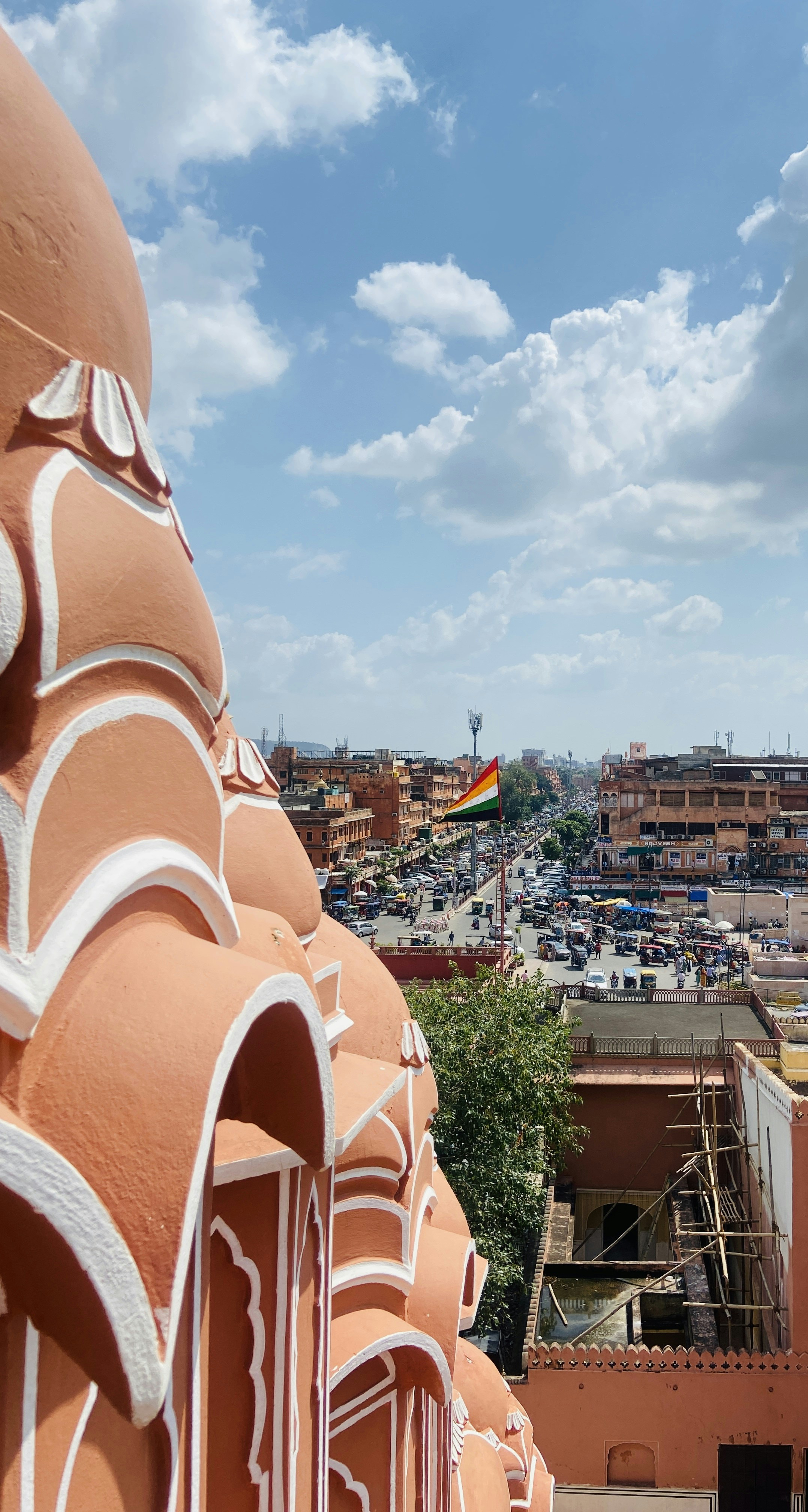 Terracotta Arches Over a Busy Street, Rainbow Flag Rising Above the City Pulse