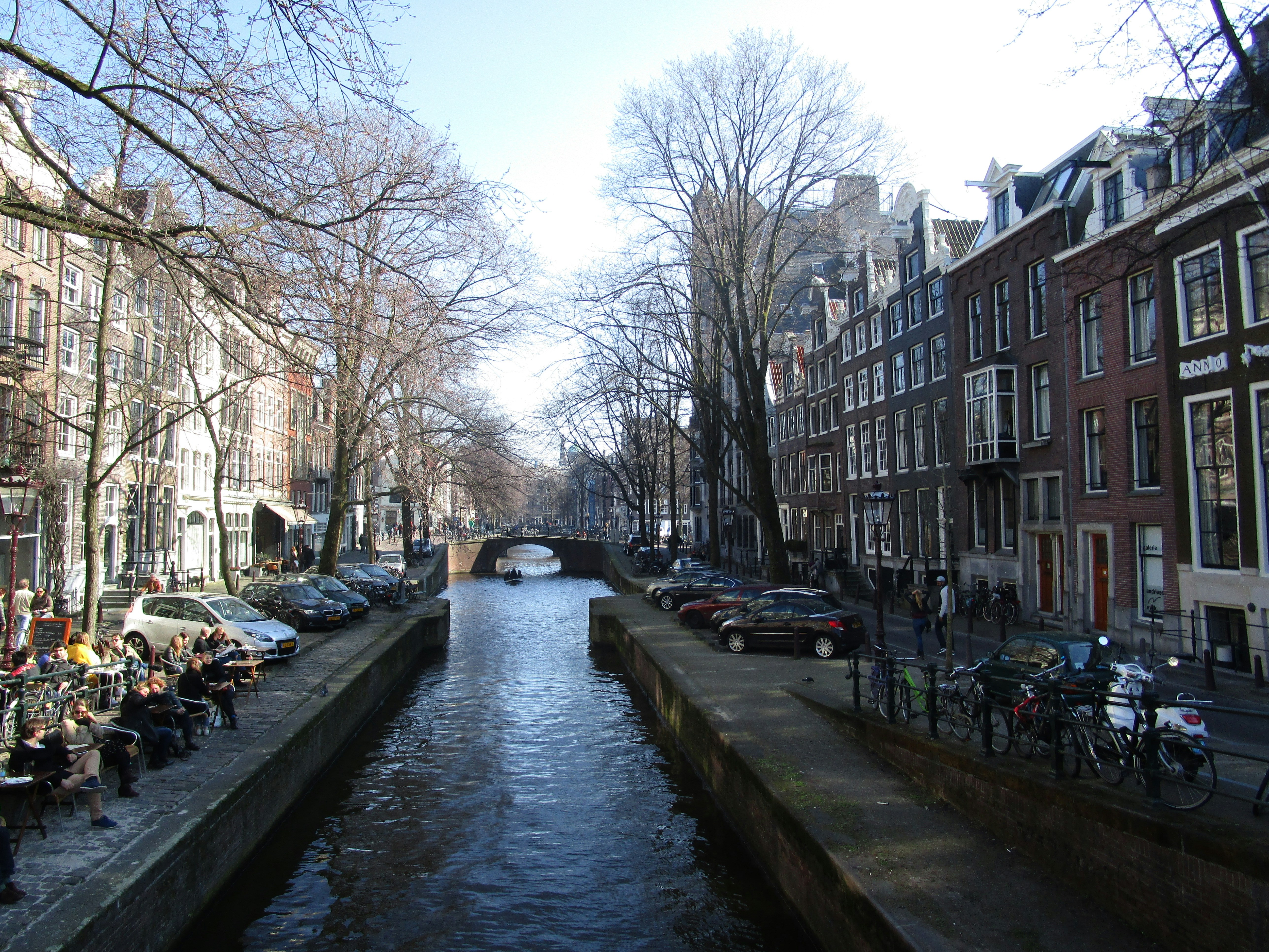 Amsterdam canal flanked by historic buildings and bare trees on a sunny winter day.