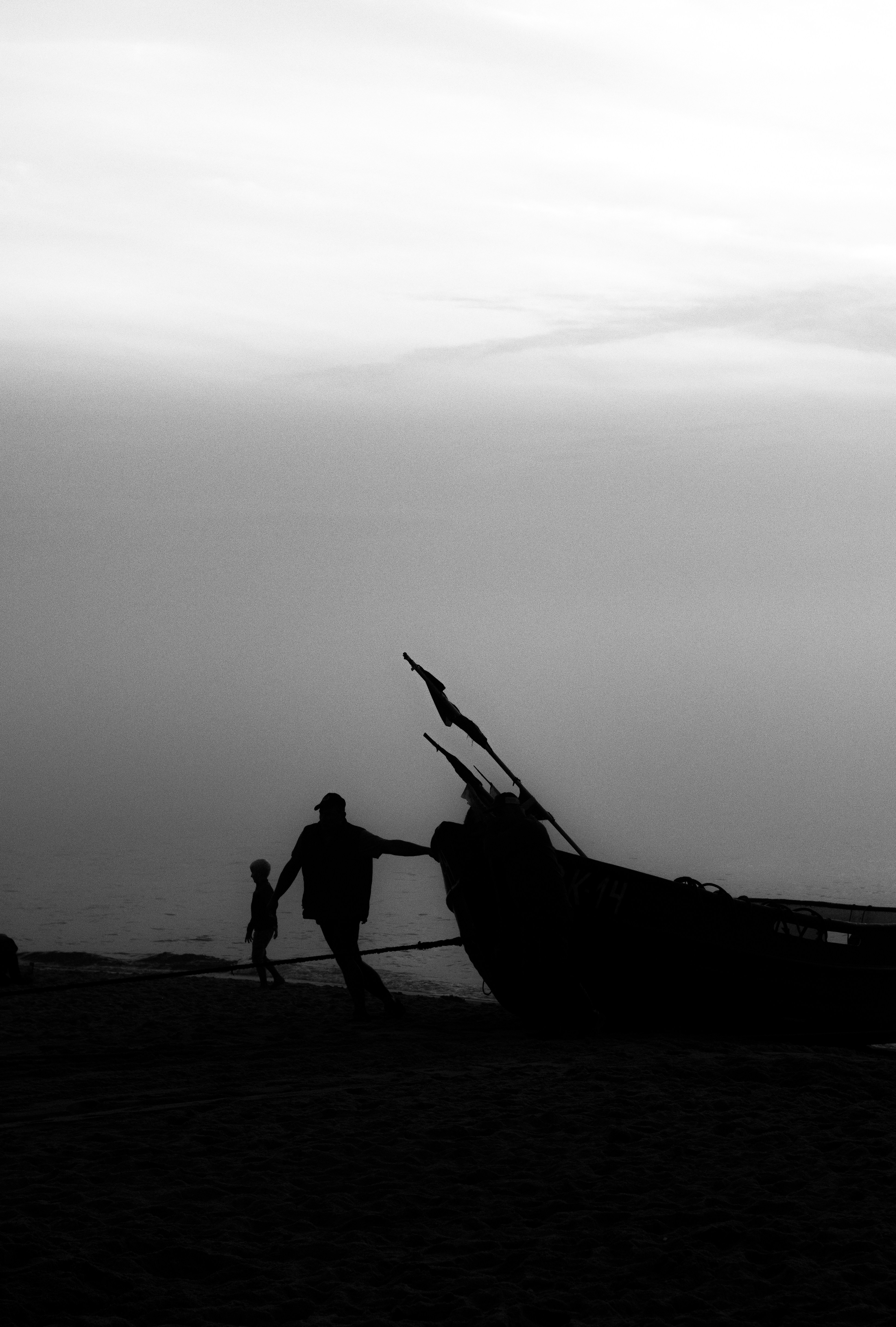 Horizon Bond: Silhouetted Figures by a Moored Boat at Dusk