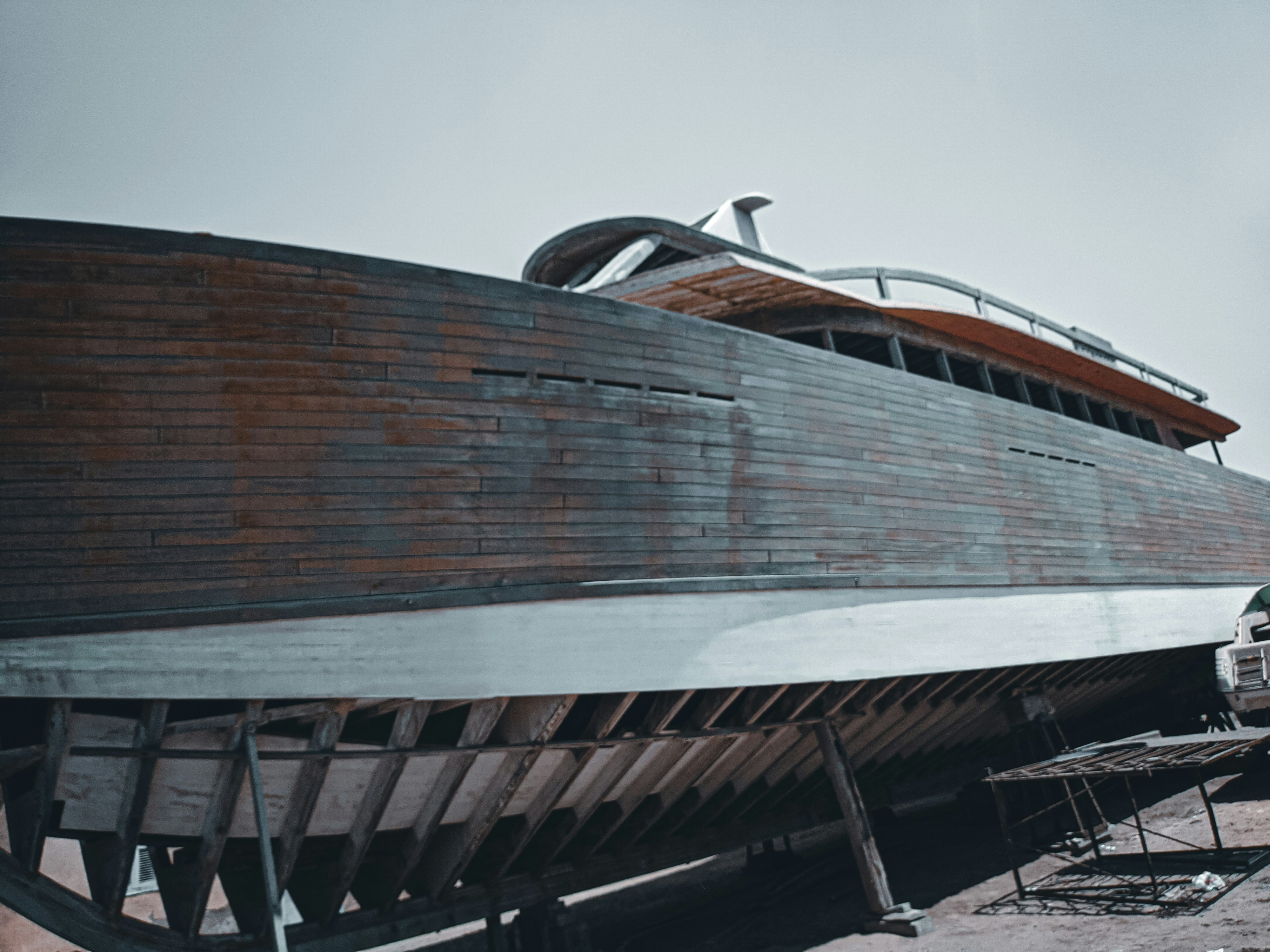 Low-angle photograph of a weathered wooden ship hull with a curved deck overhead. The composition emphasizes texture and architecture of maritime design.