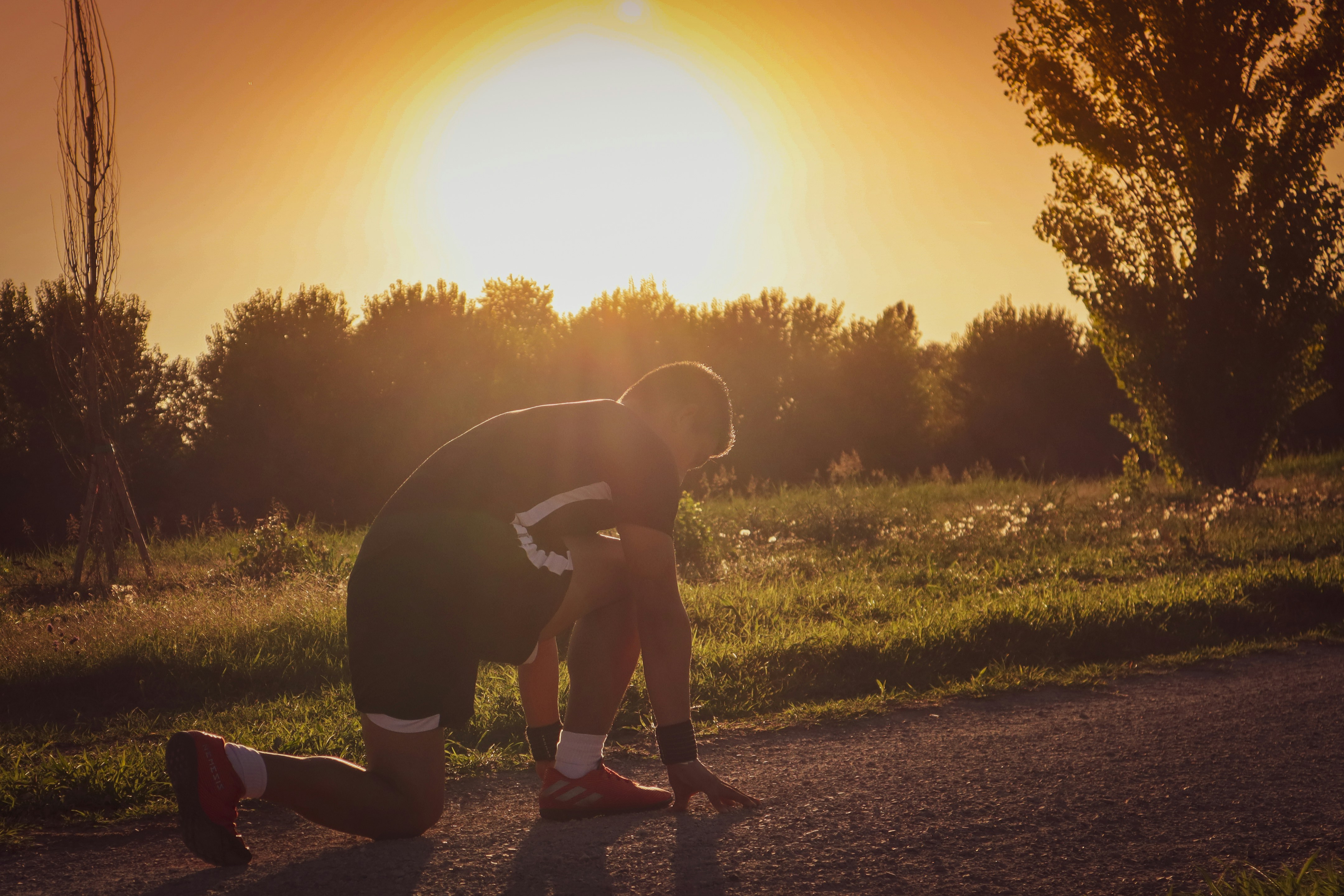 Athlete preparing for a run against a vibrant sunset backdrop, highlighting determination and focus.