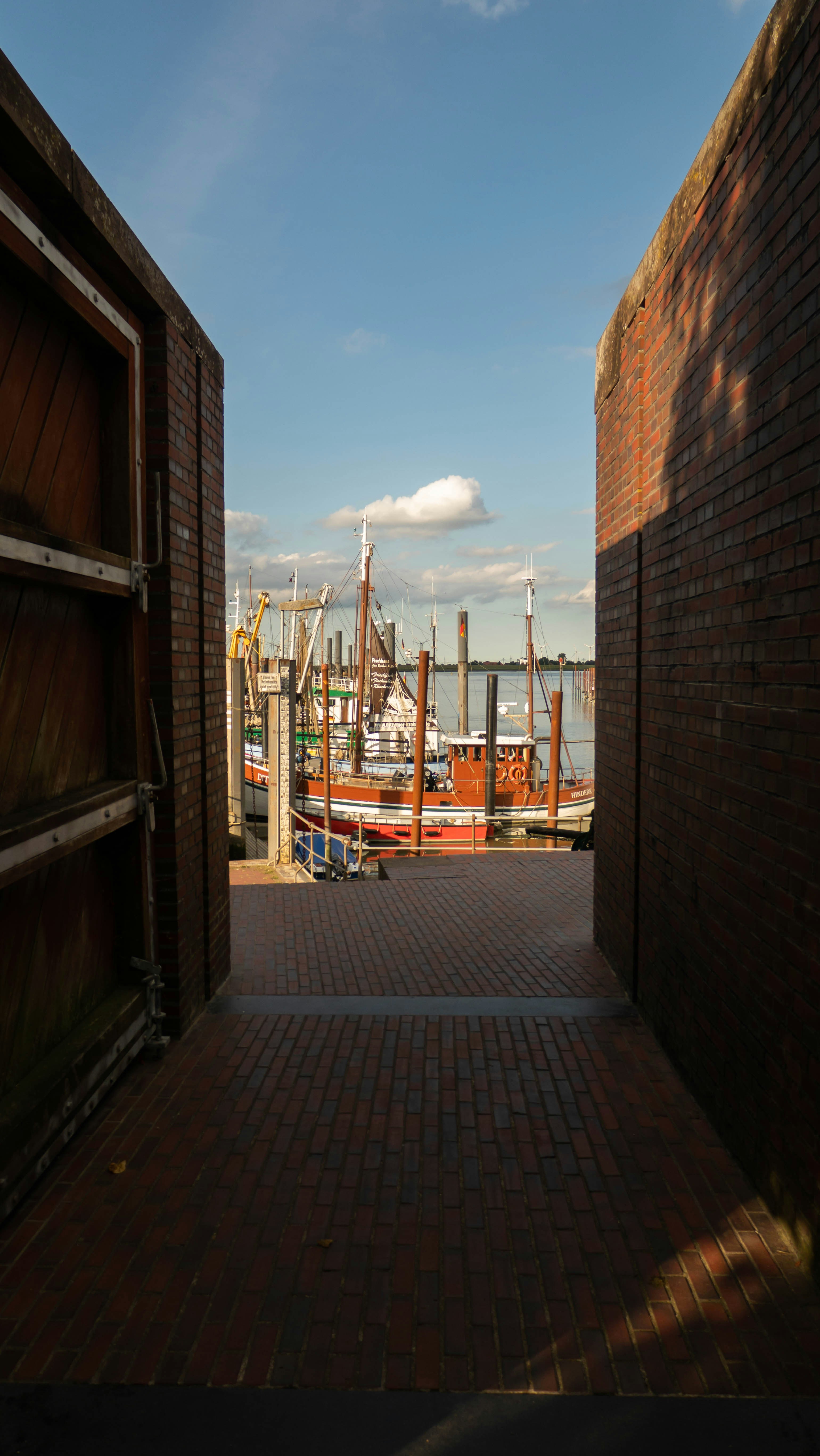 a brick walkway with boats in the background