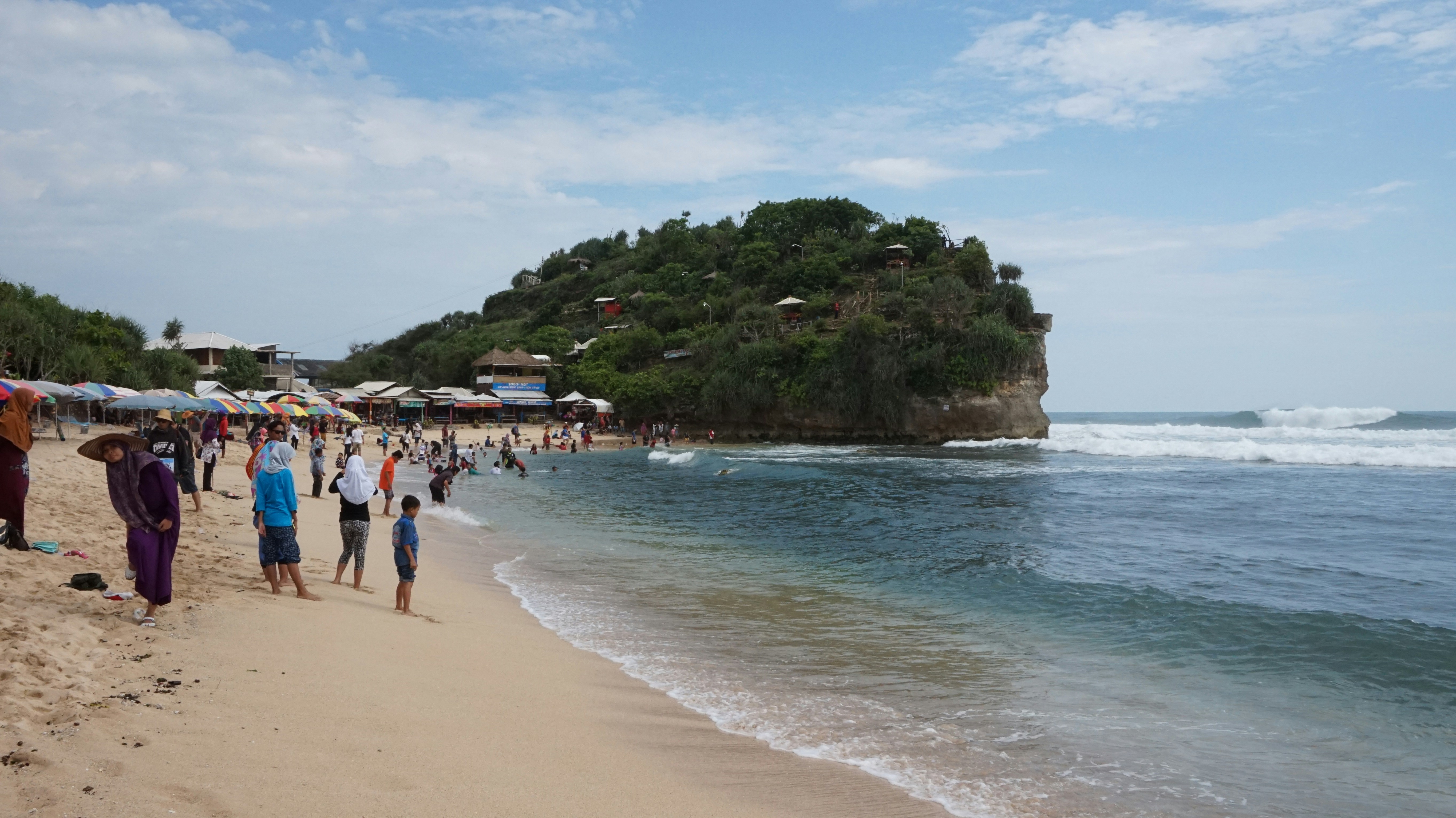 Sunlit Beachfront Village: People, Surf, and Cliffside Cove