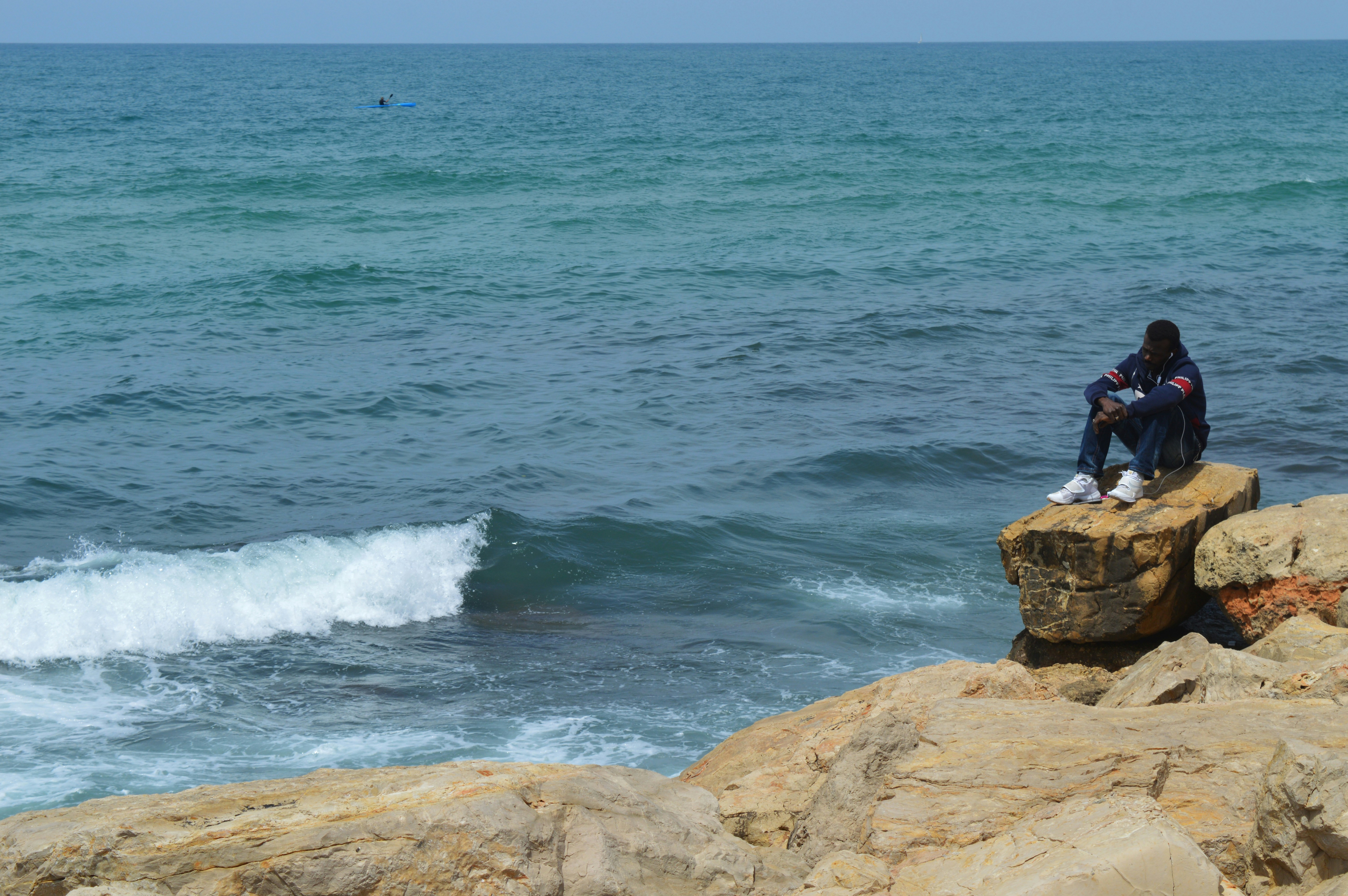 Coastal Quiet: Two figures perched on sunlit rock overlooking the sea