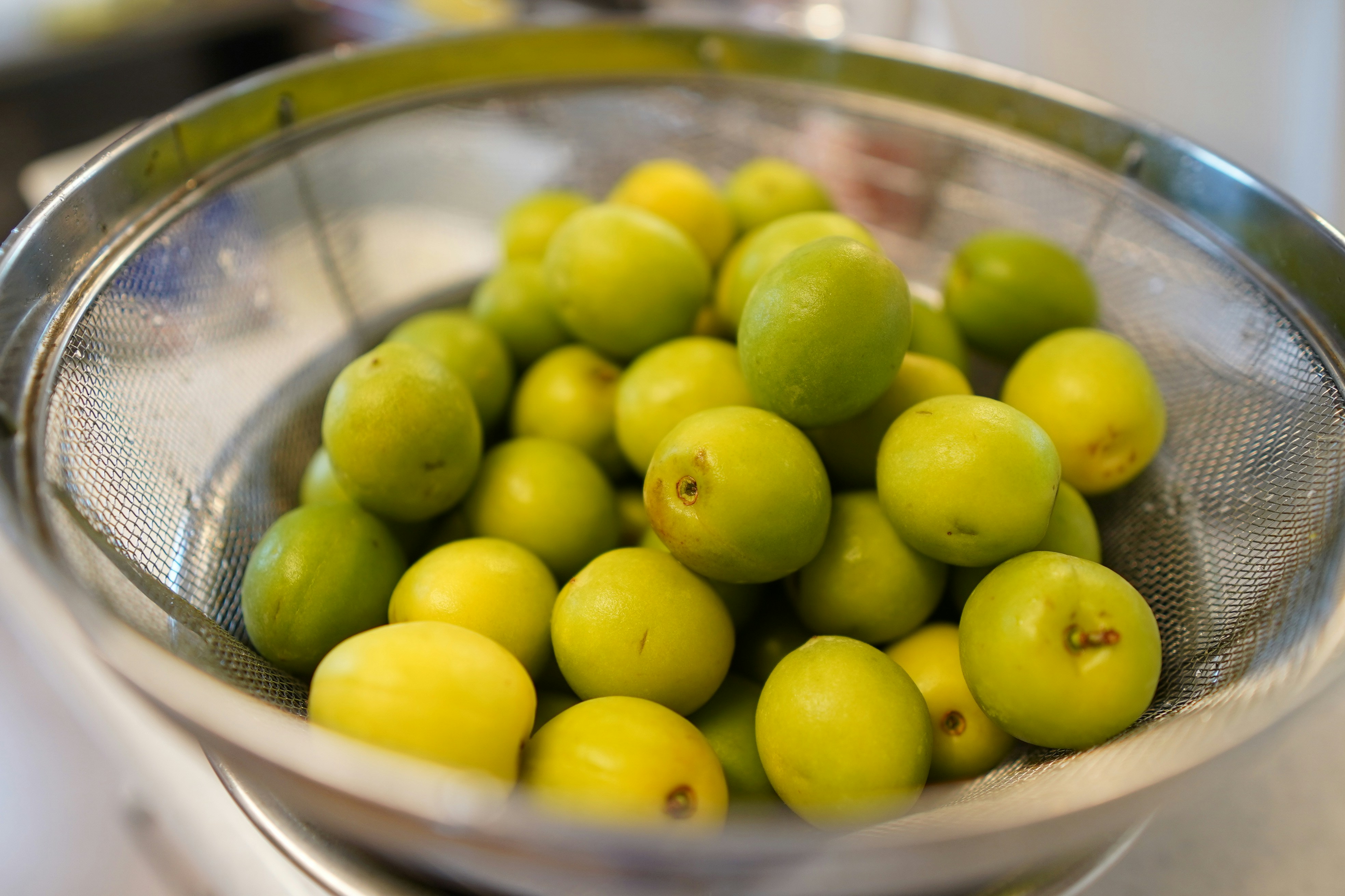 Fresh limes and lemons arranged in a colander, showcasing their vibrant hues and textures. Perfect for culinary inspiration.