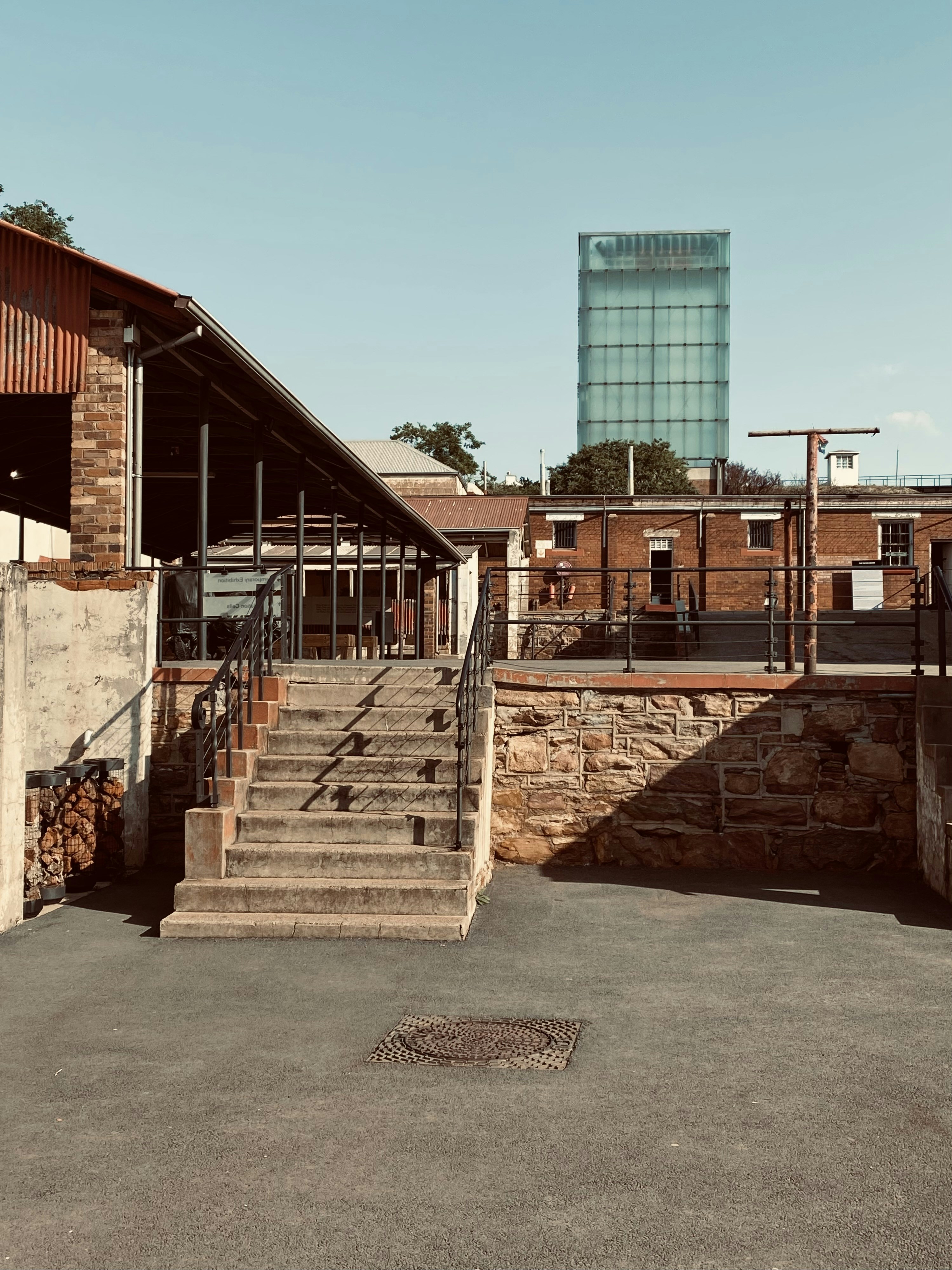 Concrete stairs leading to a modern glass building, surrounded by historical architecture and vibrant urban elements.
