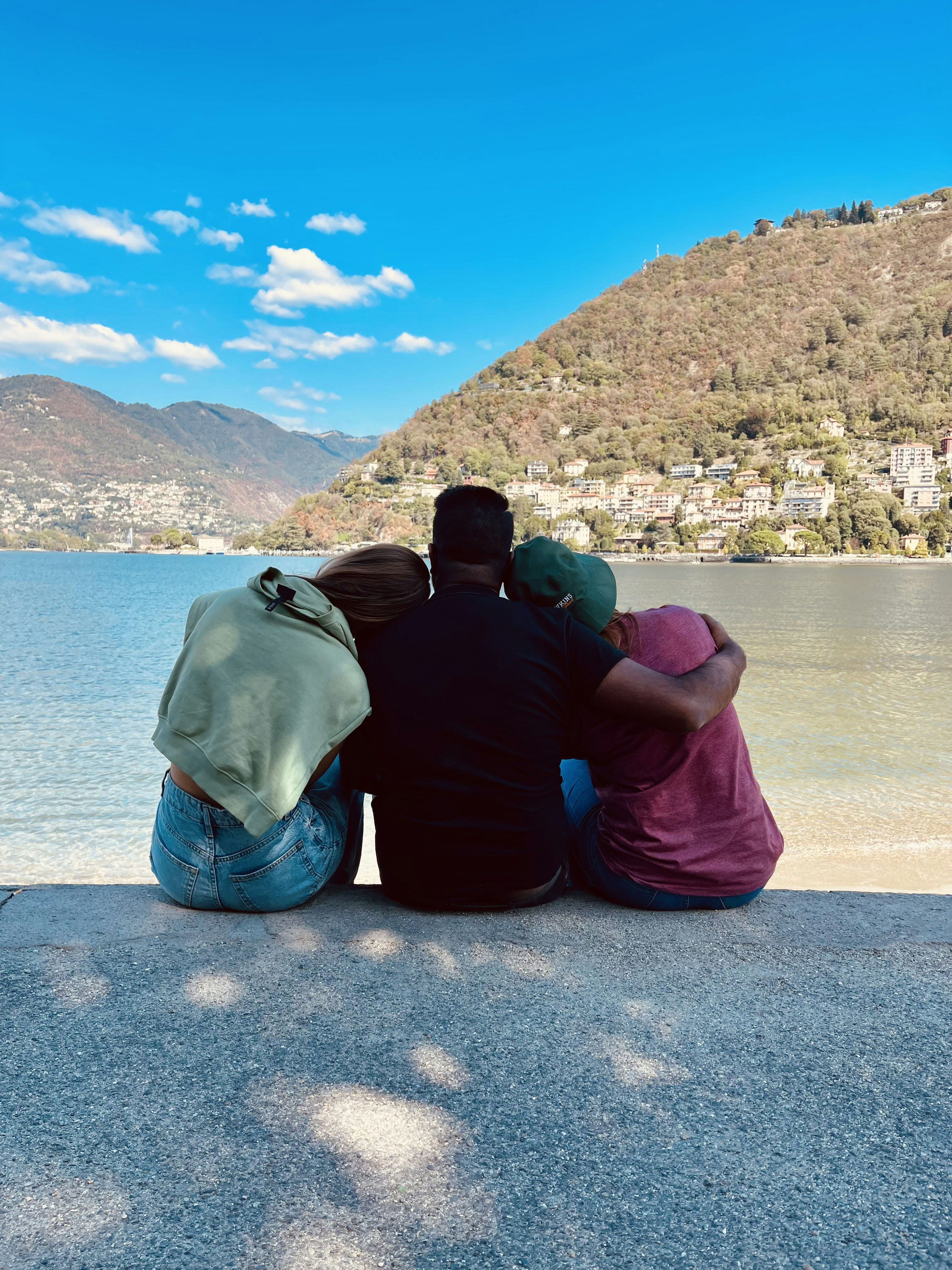 A group of people sitting on a rock ledge overlooking a body of water ...