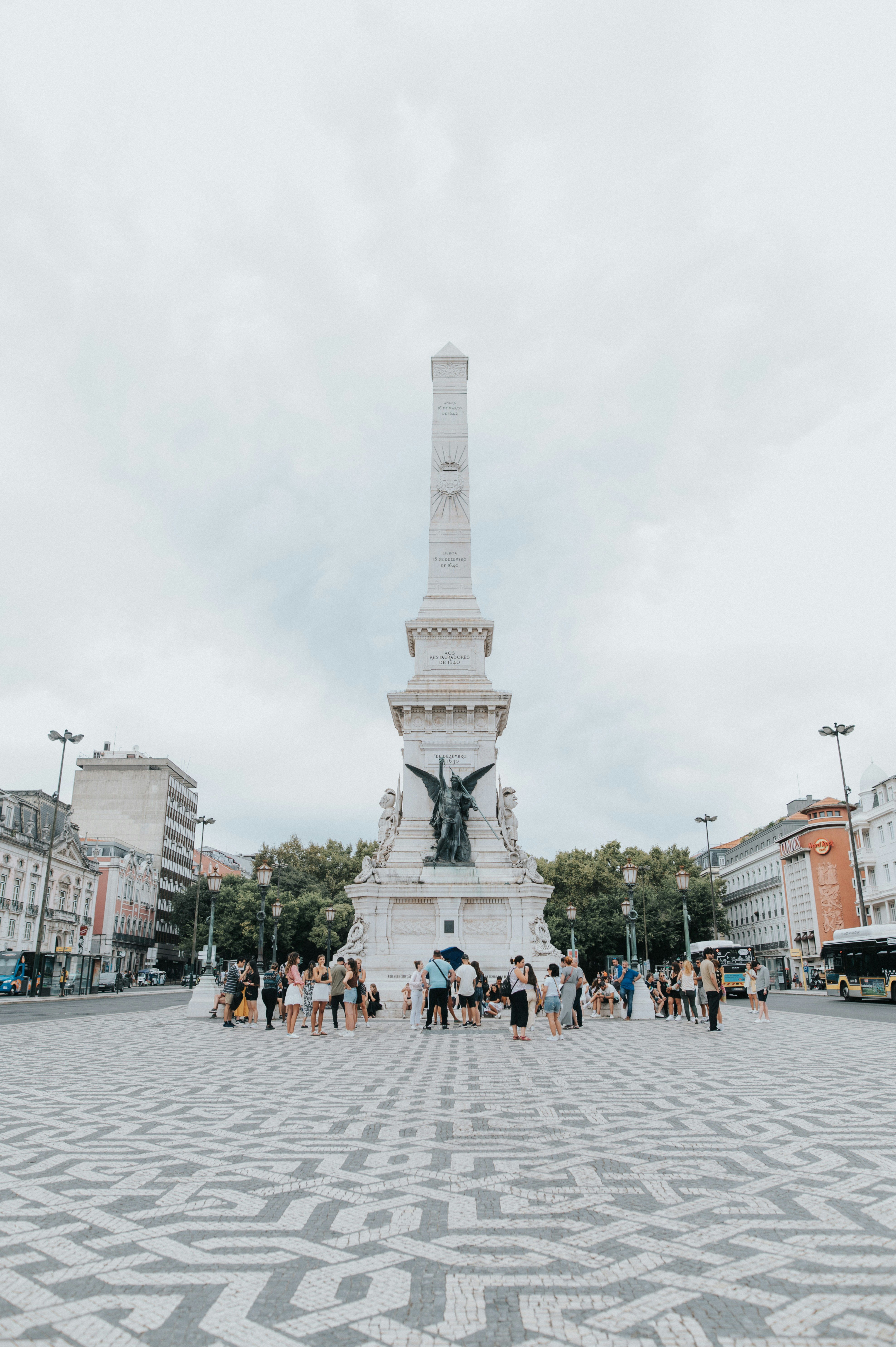 A large group of people standing around a tall statue photo – Free ...