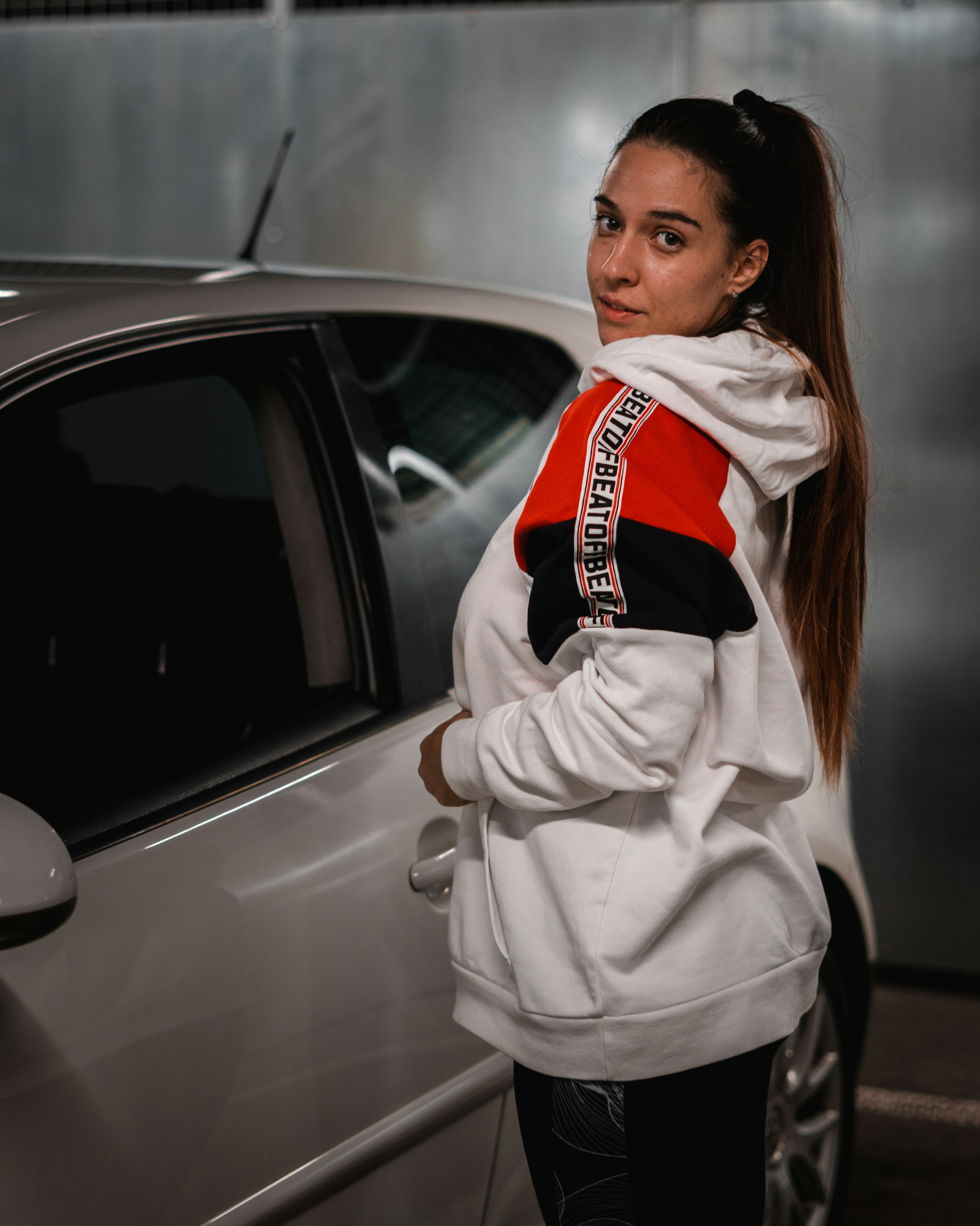 Hooded Confidence by the Silver Car in a Dim Garage