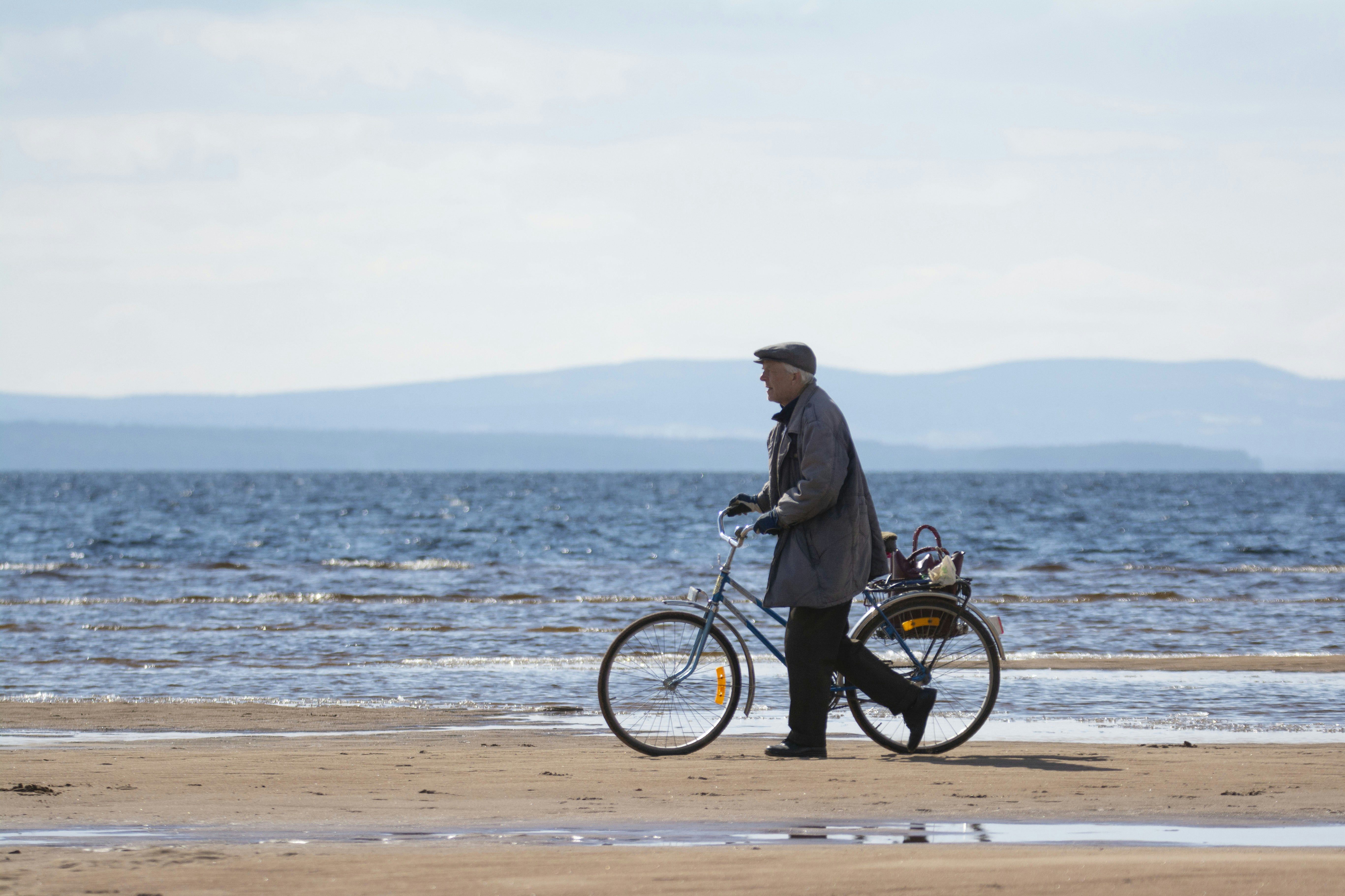 Seaside Symmetry: A Man Walks With His Bicycle Along the Wind-Swept Beach