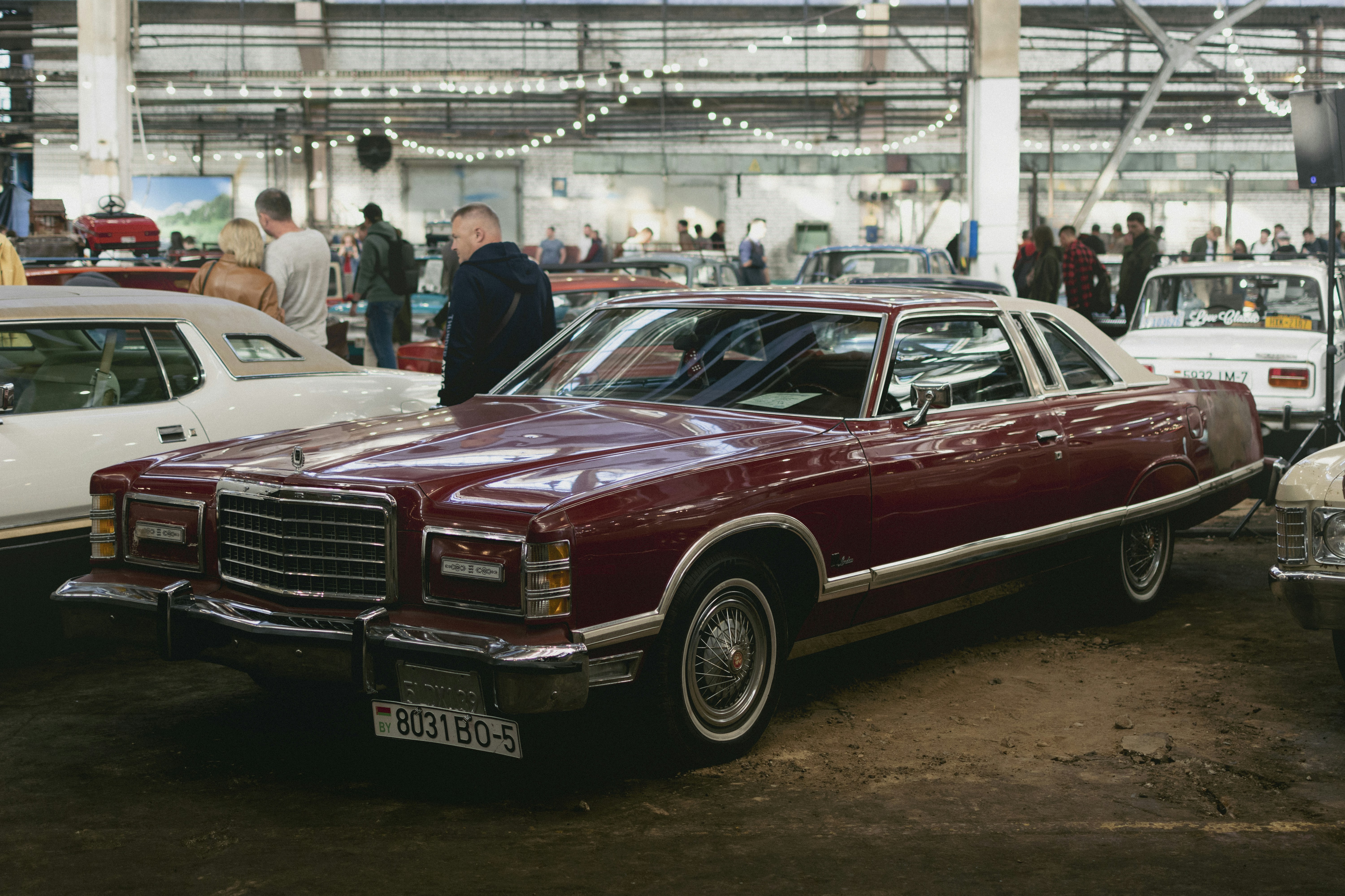 Maroon Classic: A Vintage Coupé Resting Among Painted Voices