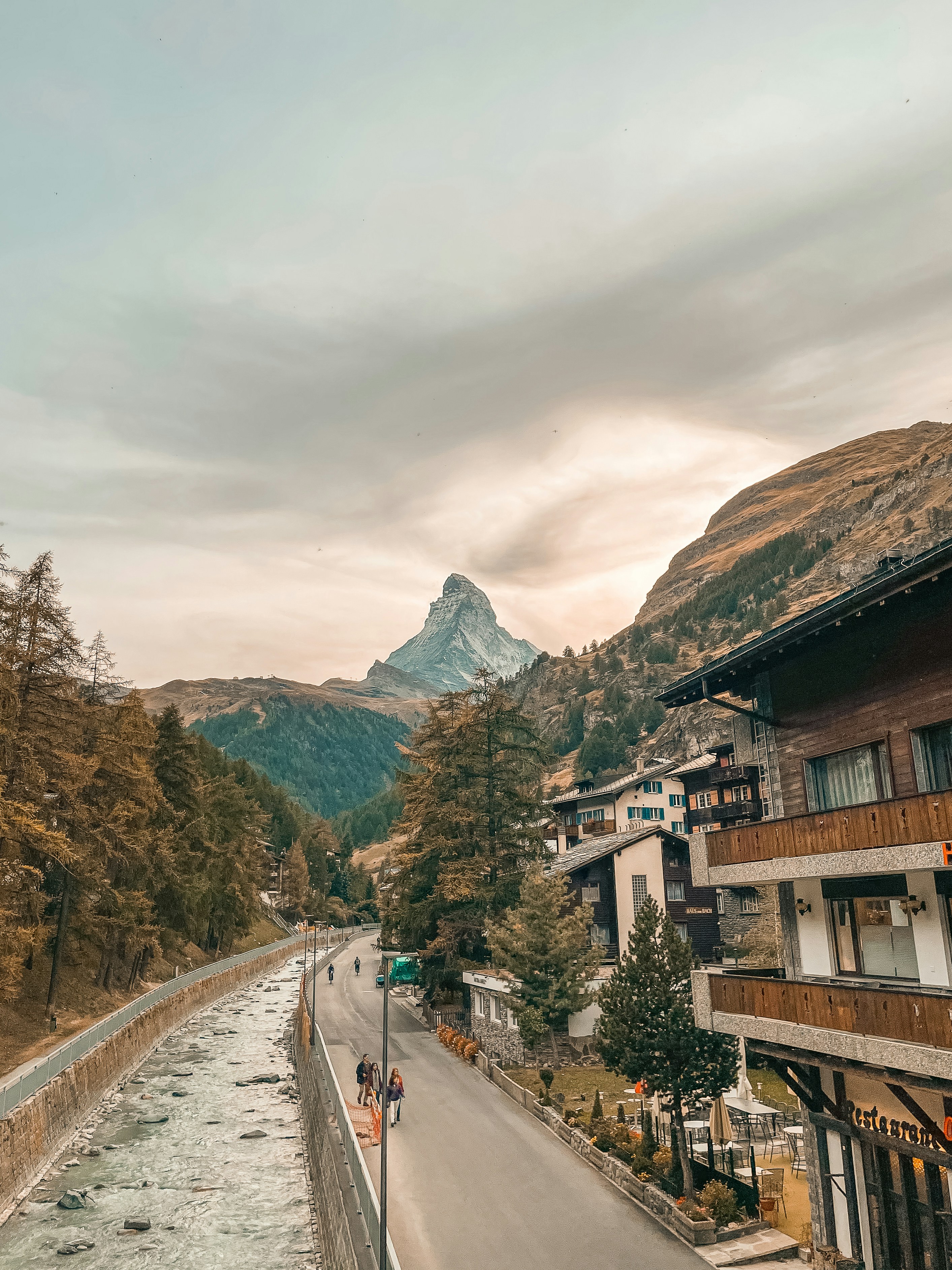 Alpine Quiet: Timbered Village Beneath a Snow-Crowned Peak by a Meandering River