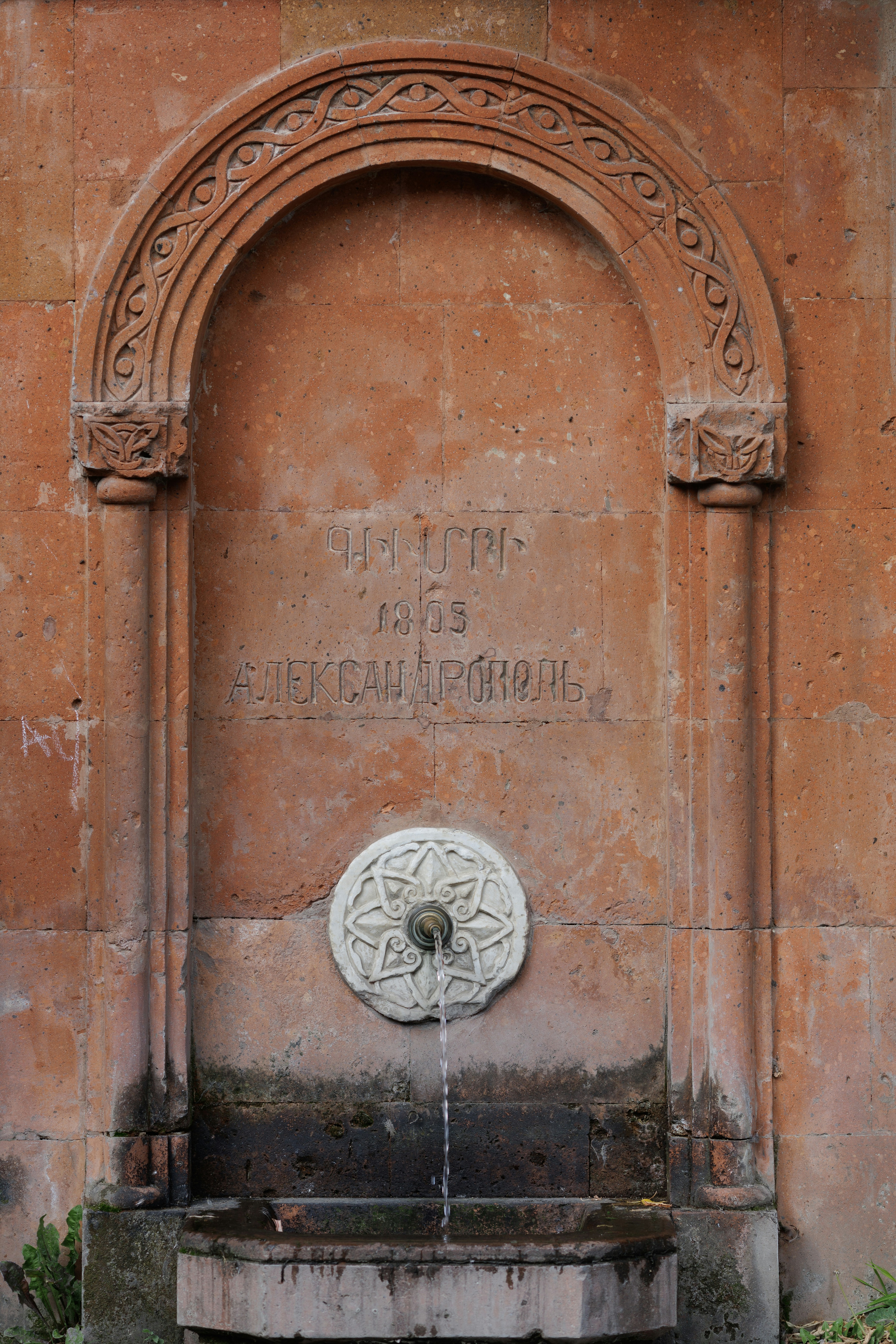 Ornate stone fountain with intricate carvings against a weathered wall.