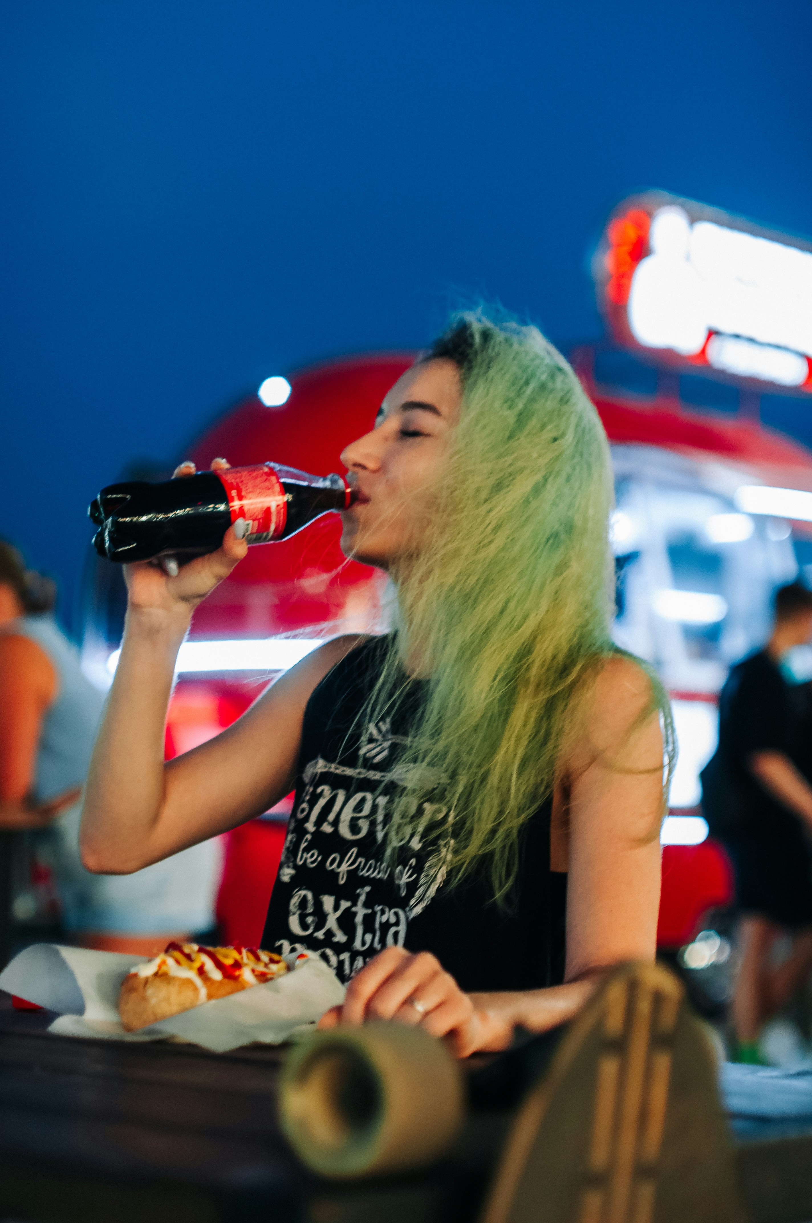 Neon-Flicked Break: A green-haired patron at a neon-lit street-food stall