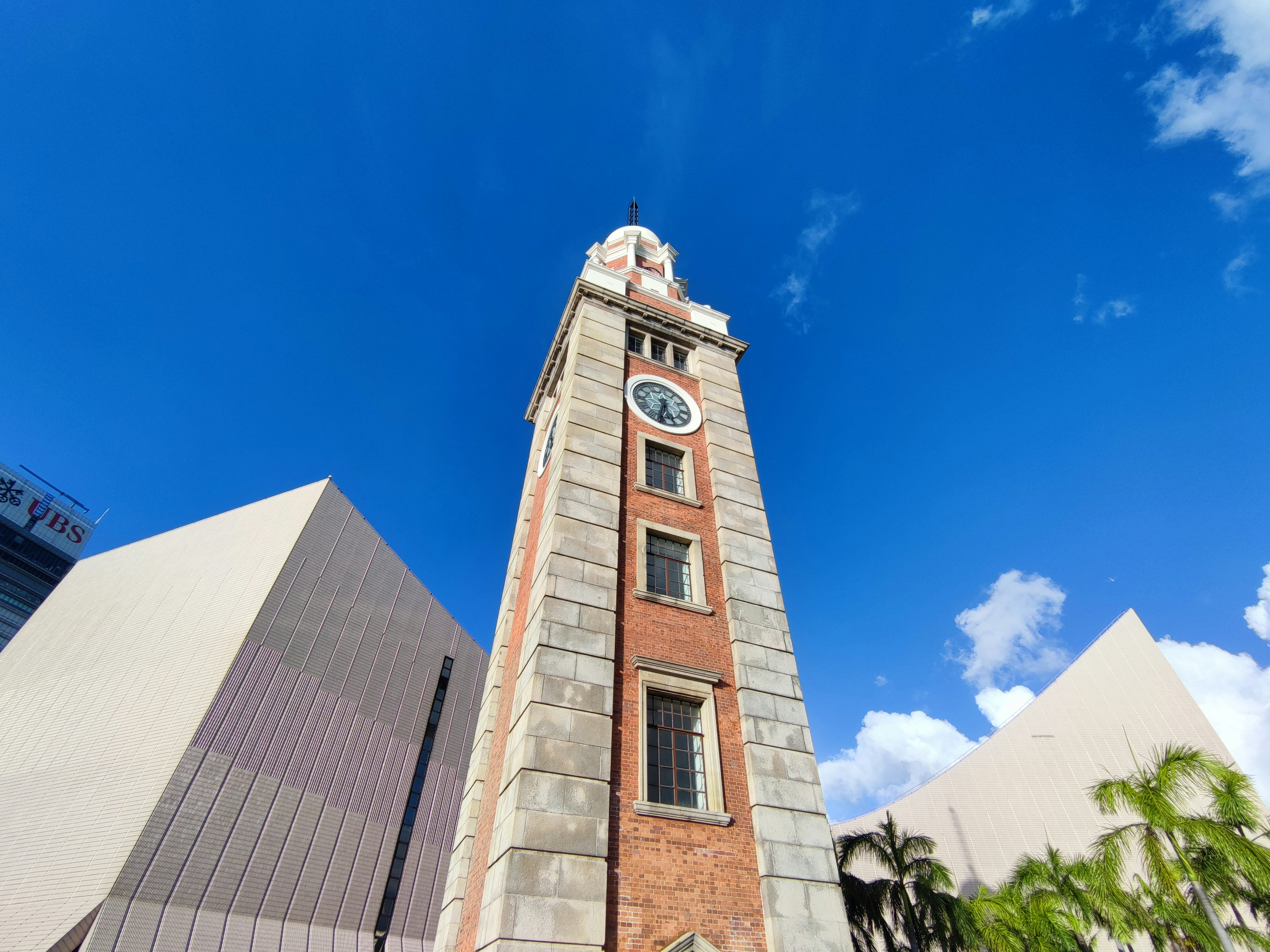 The Clock Tower of the old Tsim Sha Tsui Kowloon- Canton(Guangzhou) Railway Station was left behind as a historical and touristic site after the railway station was moved to Hung Hom. The 44 metres red brick and granite Clock Tower was built in 1915 and is a Declared Monument in Hong Kong. The building behind the Clock Tower is The Hong Kong Cultural Centre. The Clock Tower is next to the Star Ferry Pier in Tsim Sha Tsui. It is also the start of the promenade leading from Star Ferry Pier to Avenue of Stars in Tsim Sha Tsui East. The curvy building in the background is Hong Kong Cultural Centre