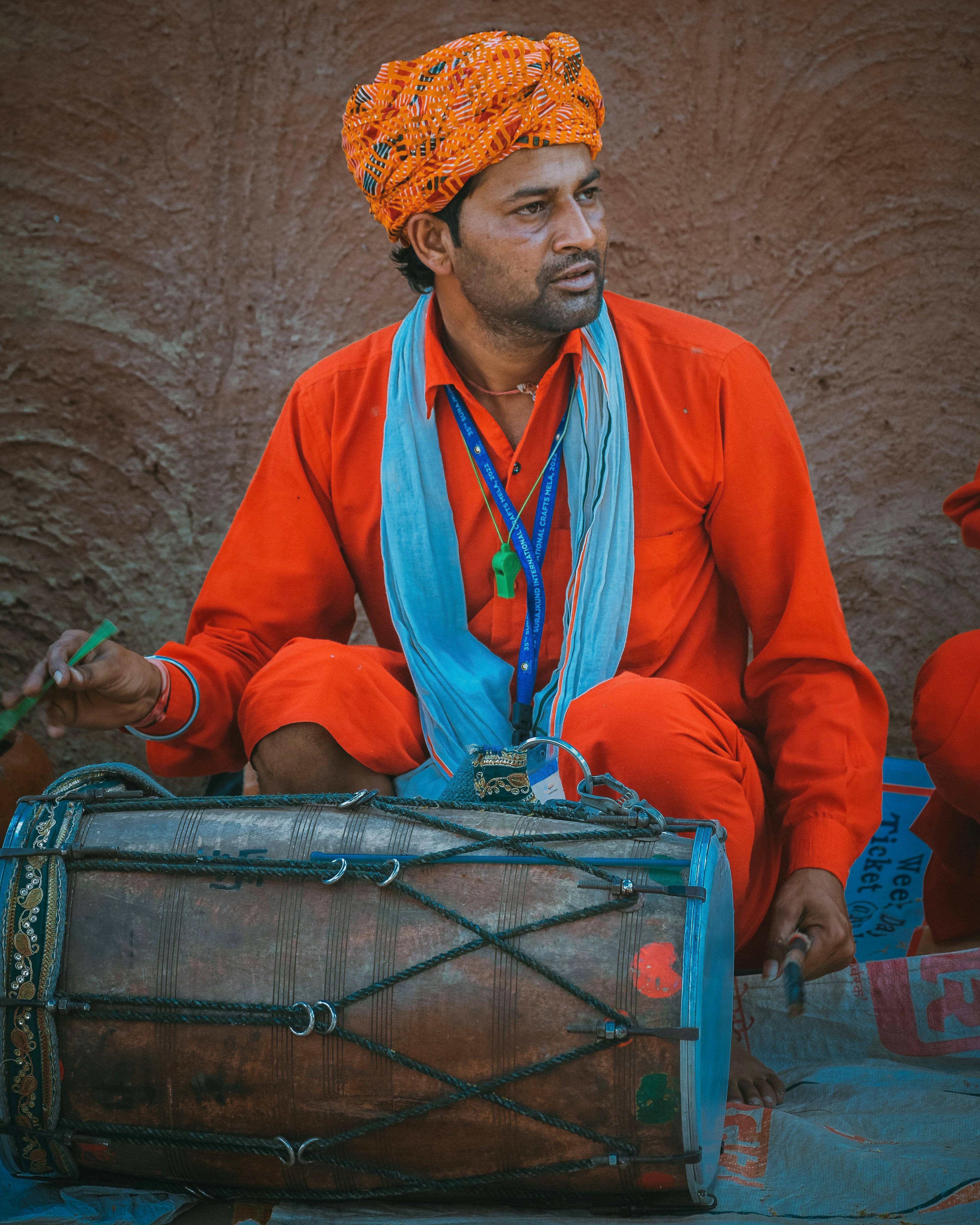 Musician in vibrant attire playing a traditional drum, embodying the spirit of cultural festivities.