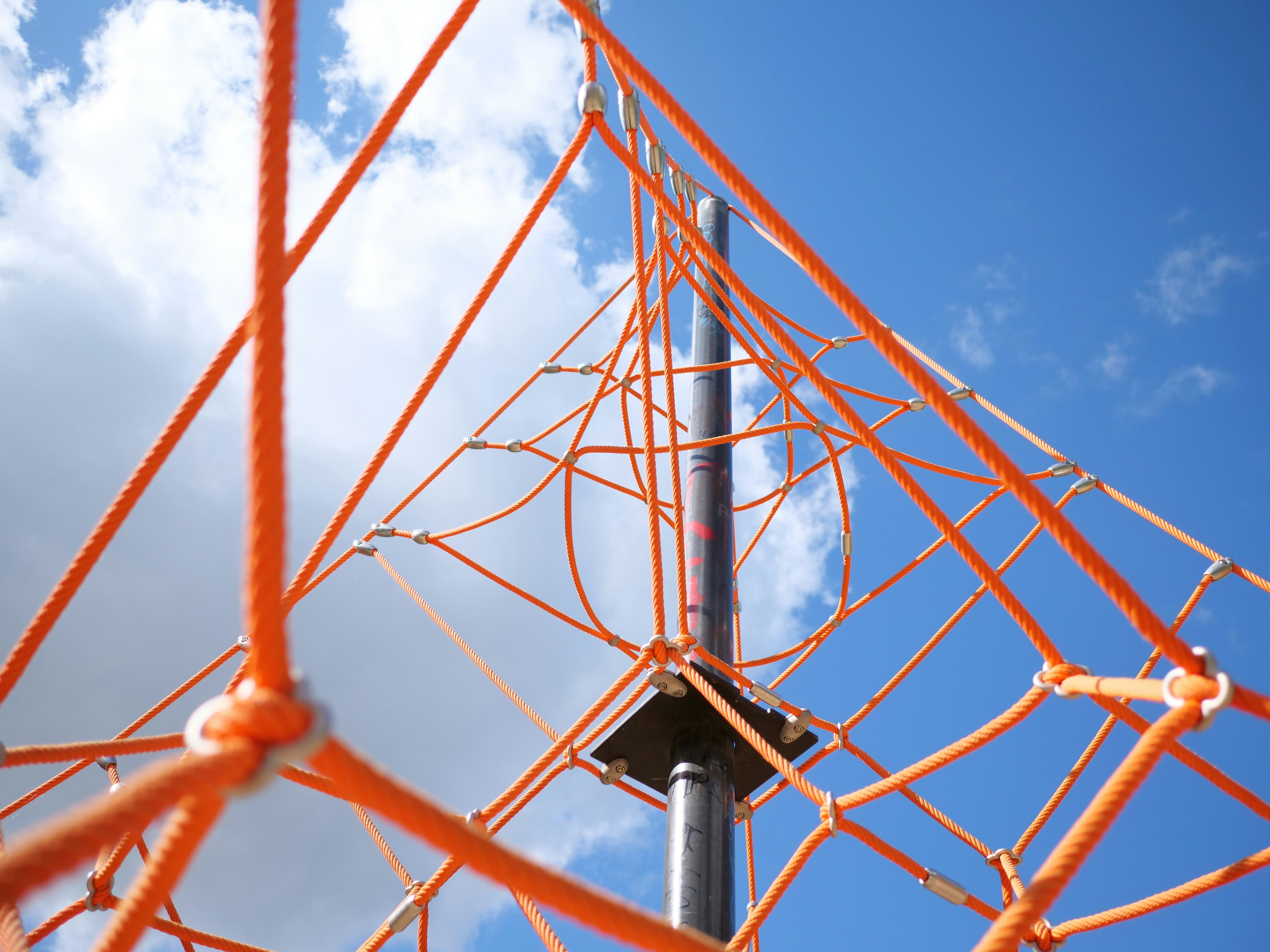 Playground - orange net and blue sky. Spielplatz - Oranges Kletternetz vor blauem Himmel.