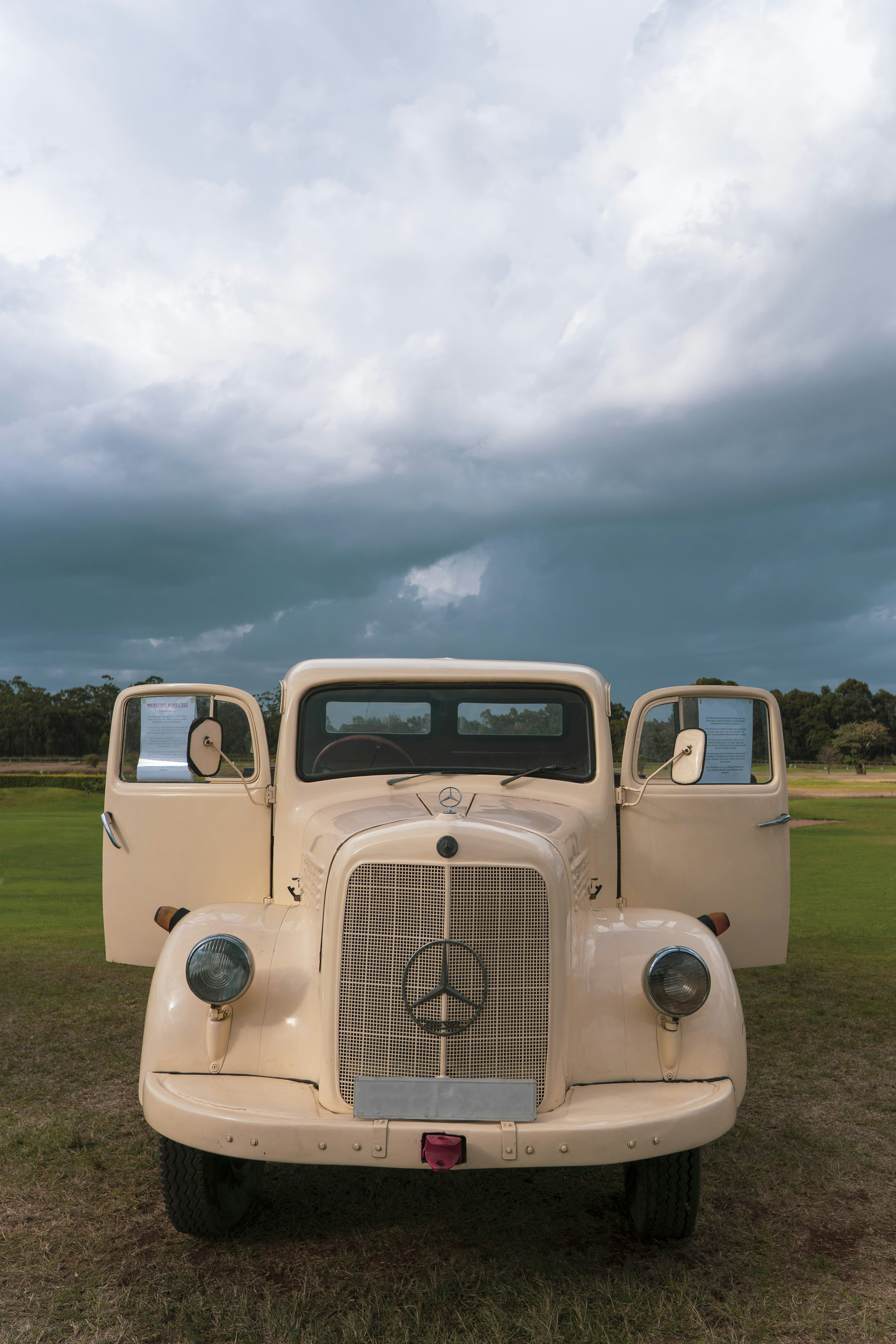 Front-Row Classic: Beige Mercedes-Benz Beneath a Tempestuous Sky in an Open Field