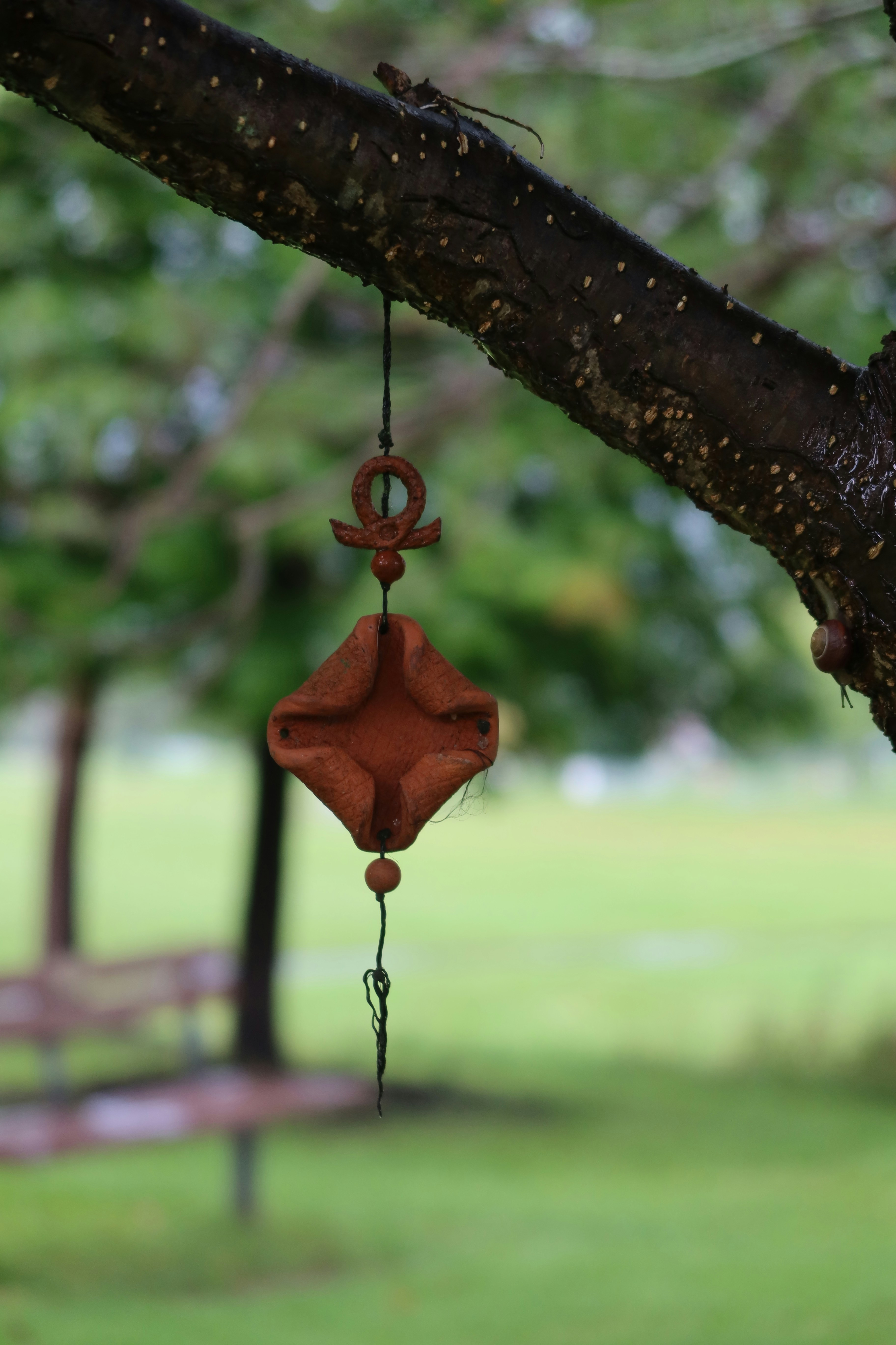 Hanging Terracotta Kinetic: a wind-charmed ornament graces a mossy branch