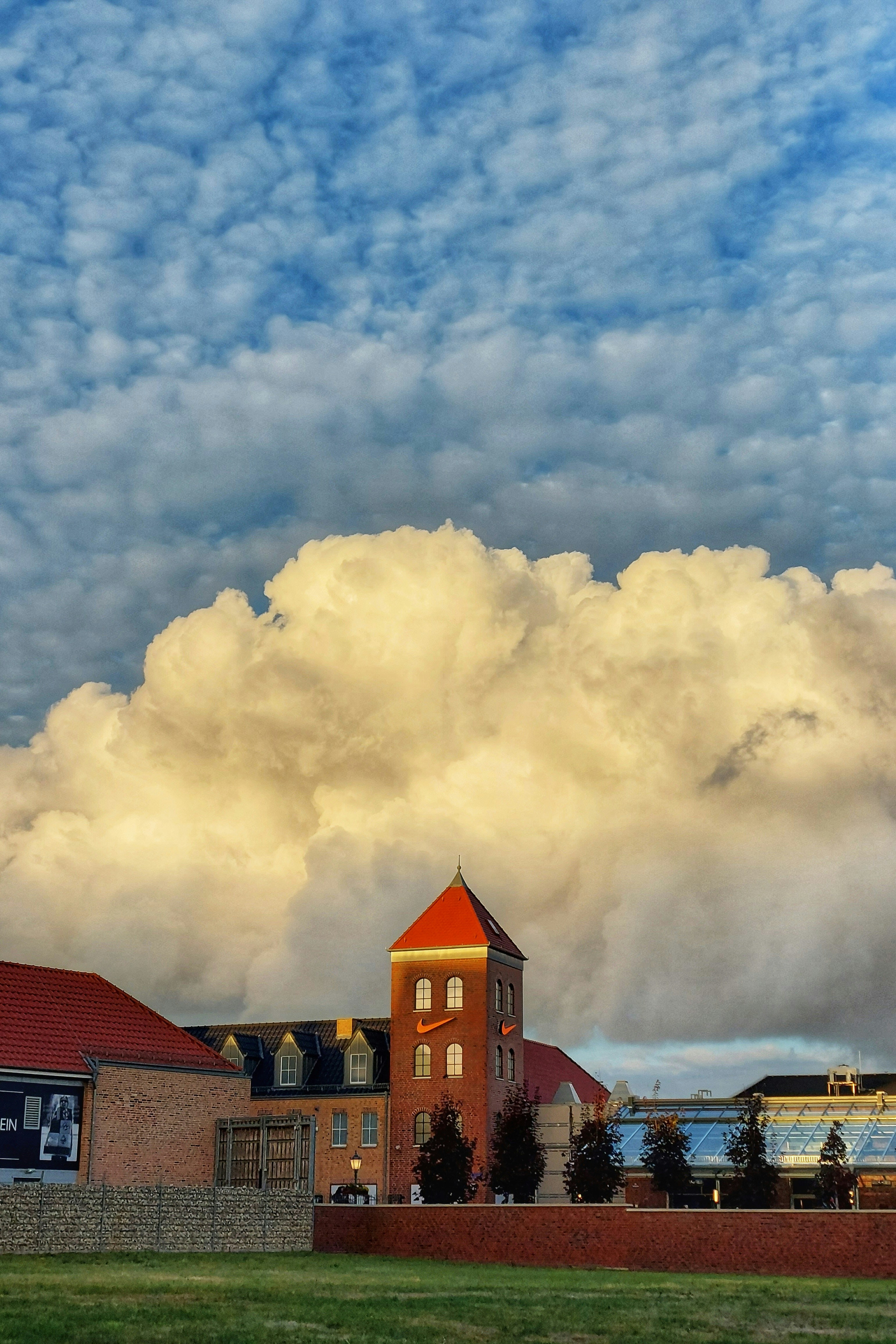 Red Clocktower Beneath a Sea of Warm Clouds at Dusk