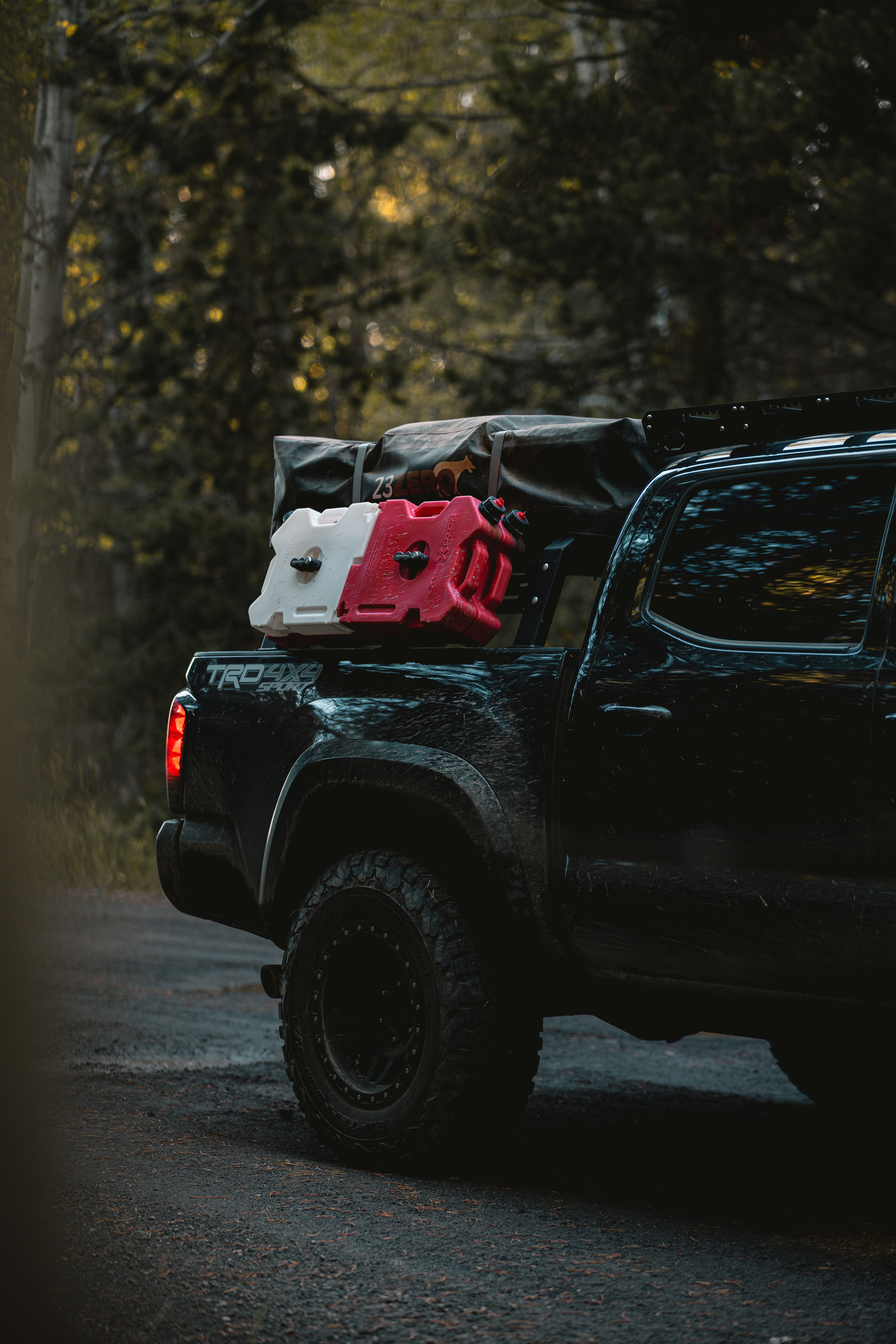 Red Jerry Can on a Mud-Splashed Pickup in a Forest Road at Dusk
