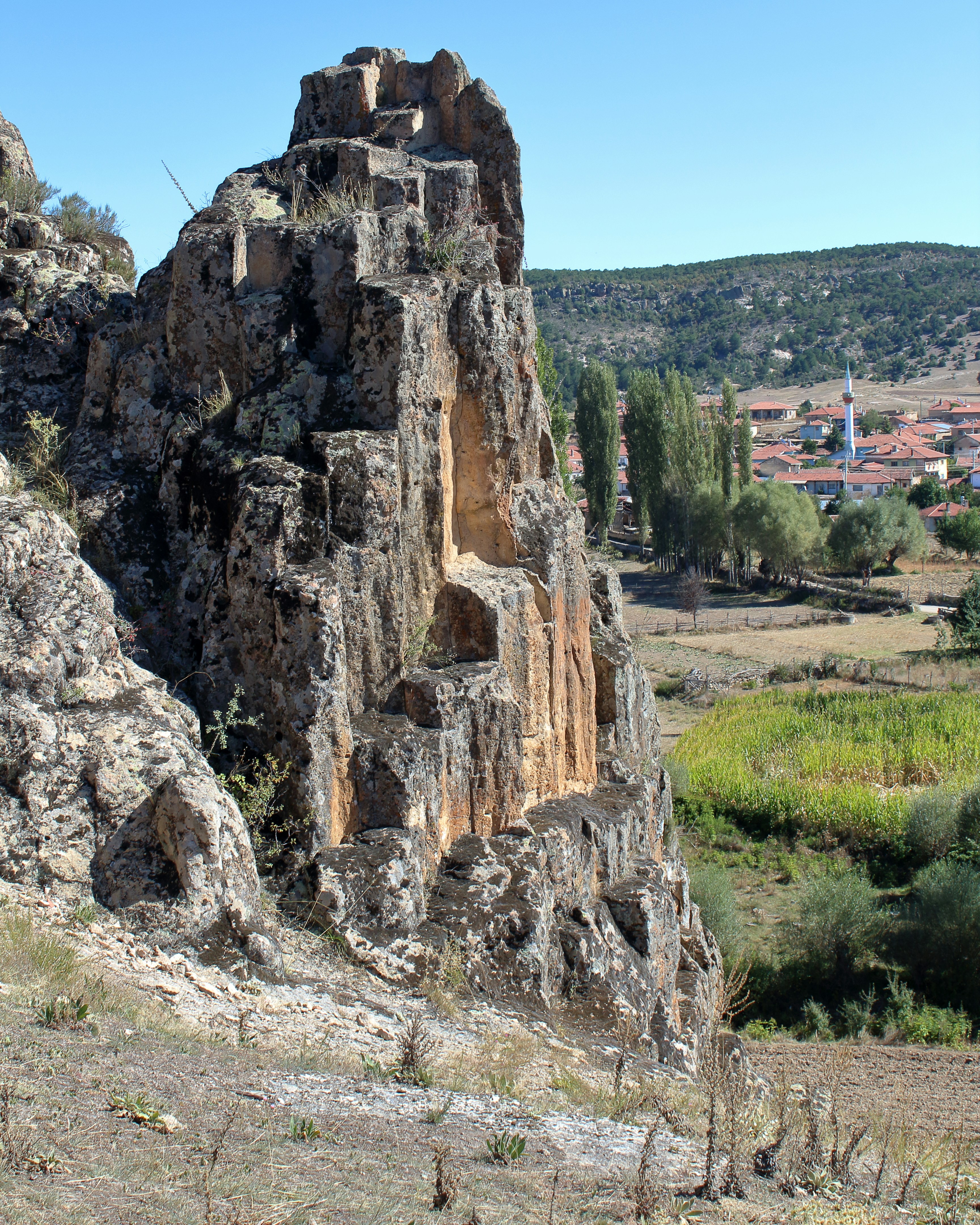 A large rock cliff with a town below photo – Free Rock formations Image ...