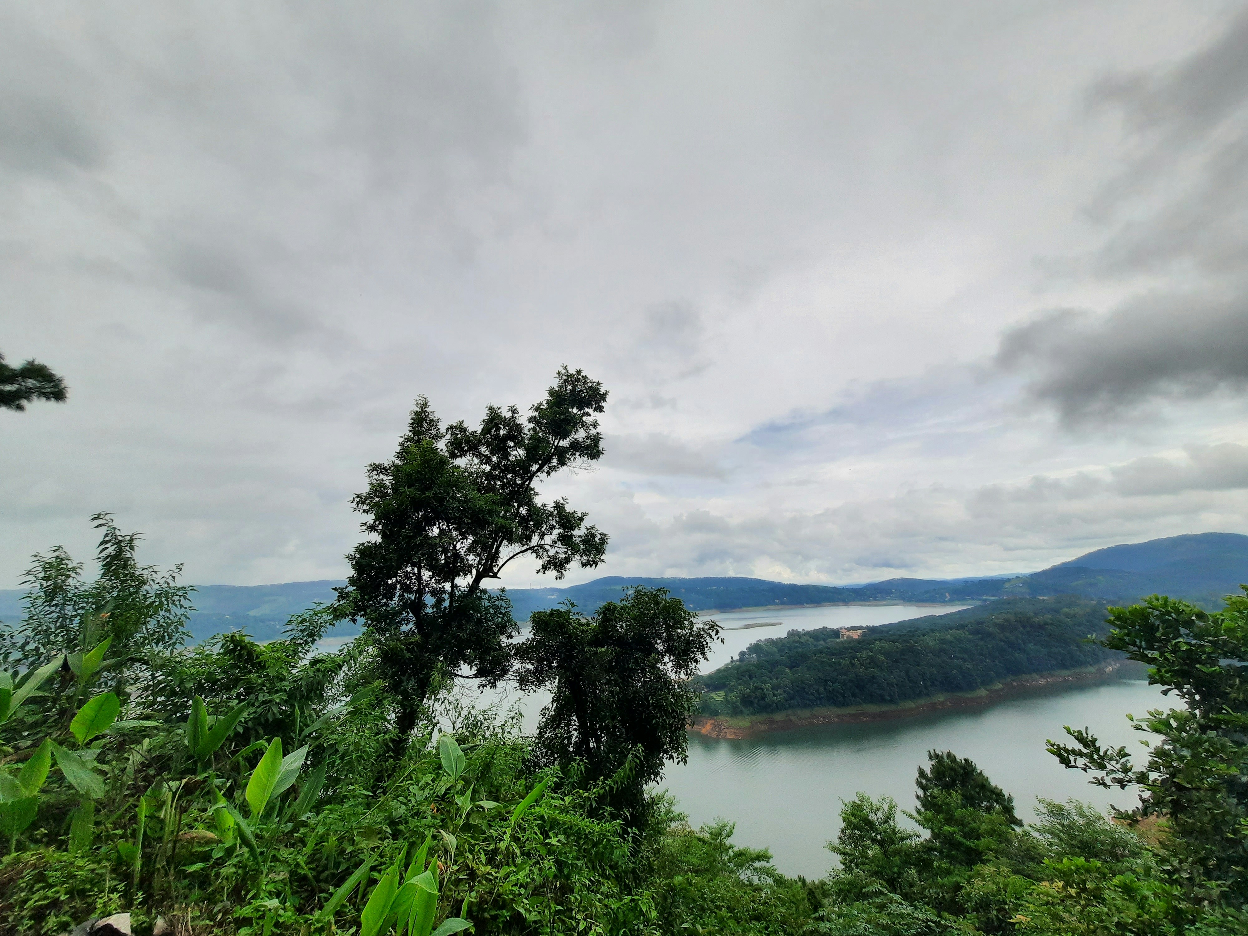Lush greenery frames a tranquil lake under a cloudy sky.